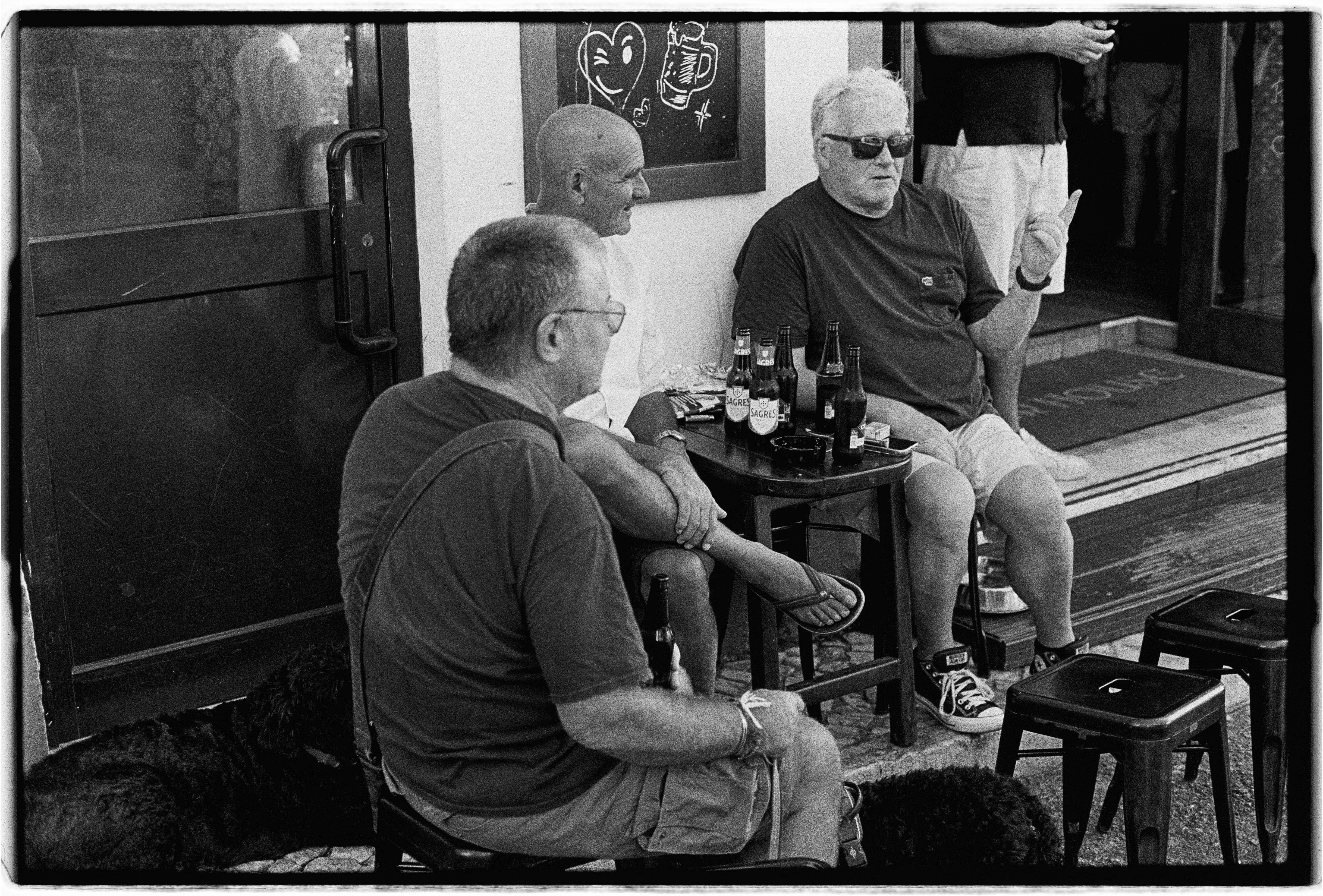 Discussion in a sunny sidewalk tavern: friends with beer