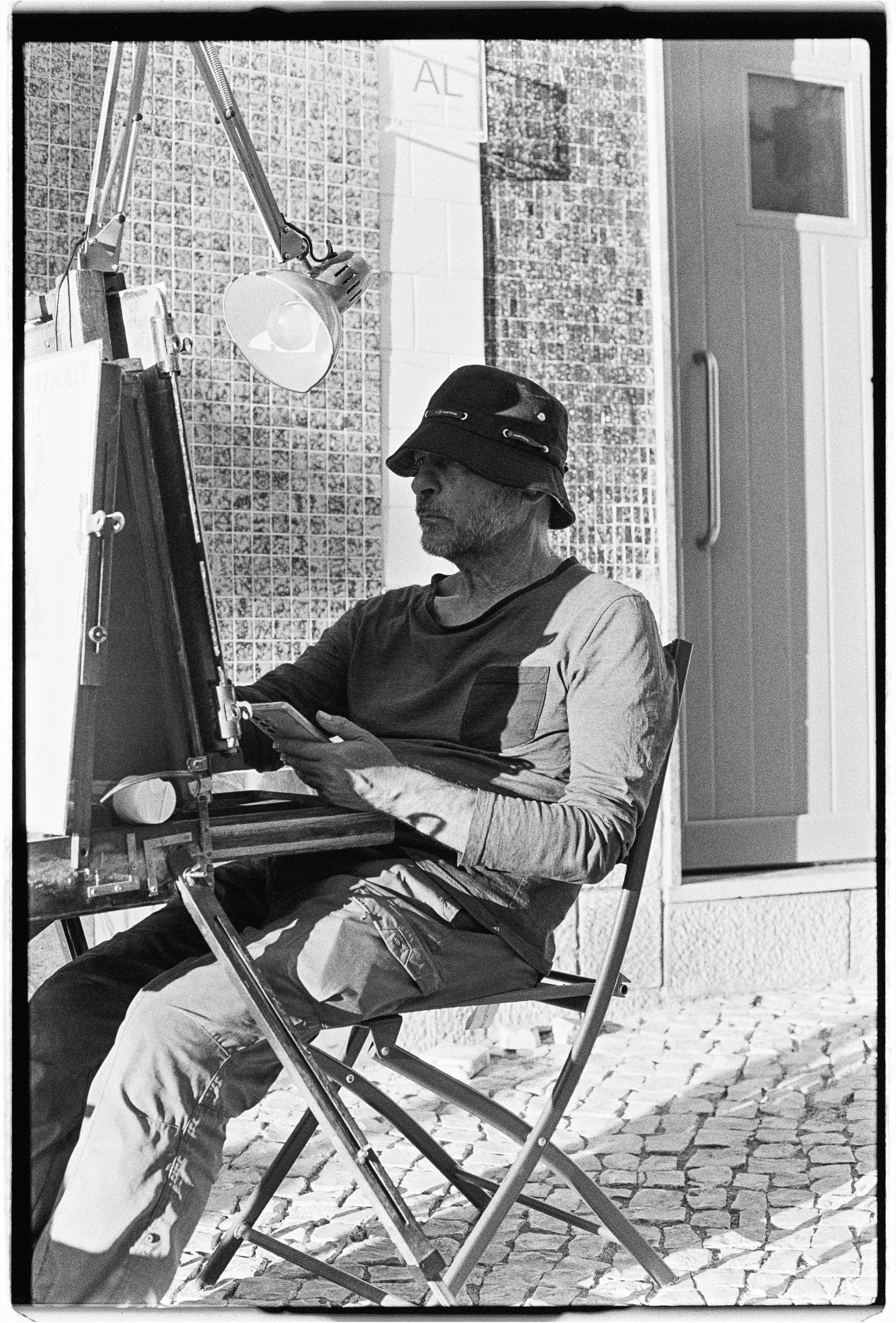 Portrait of a painter in sunlight: hands at work, hat casting a shadow