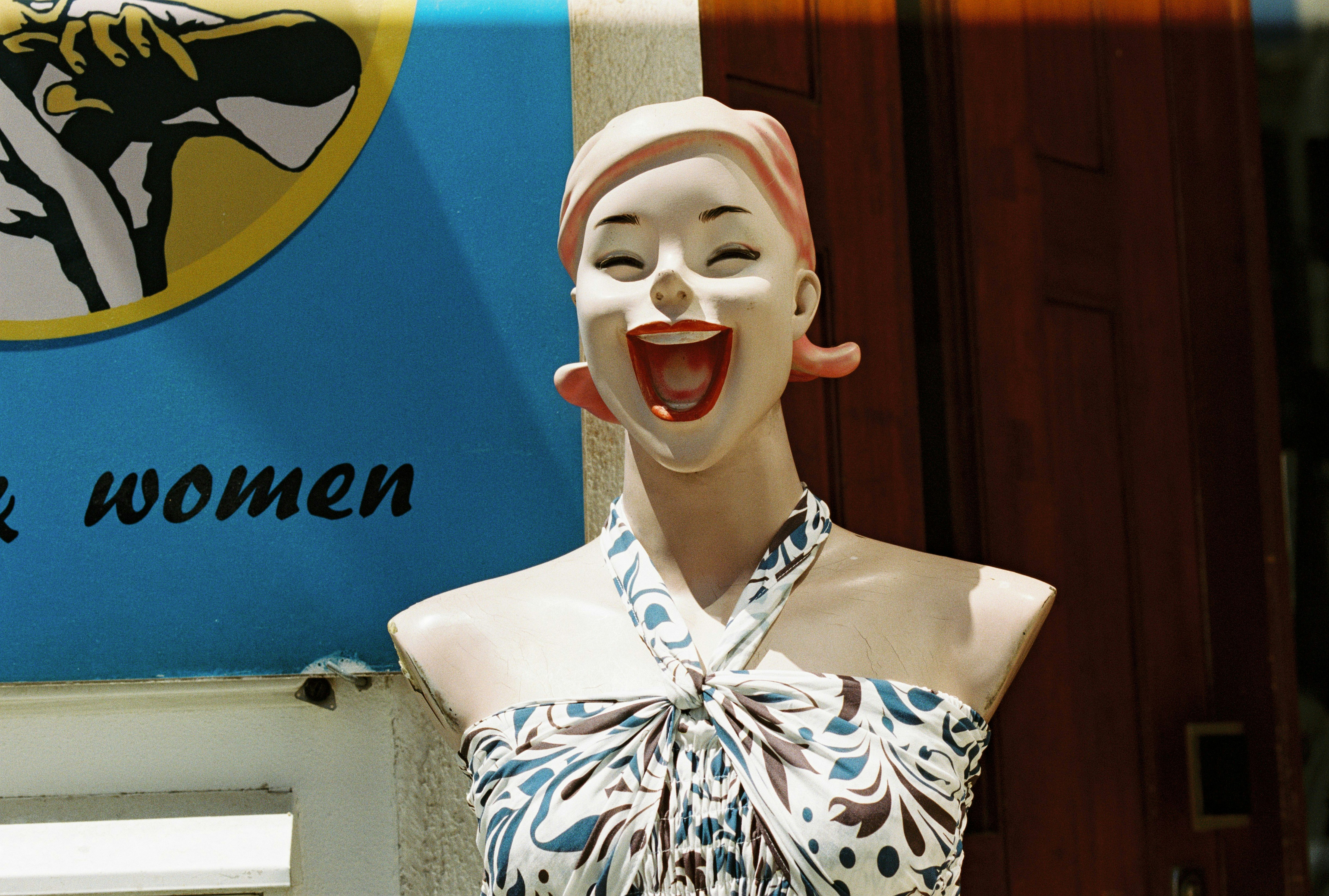 Smiling Surreal: A Decoratively Printed Bust Against a Vibrant Blue Sign