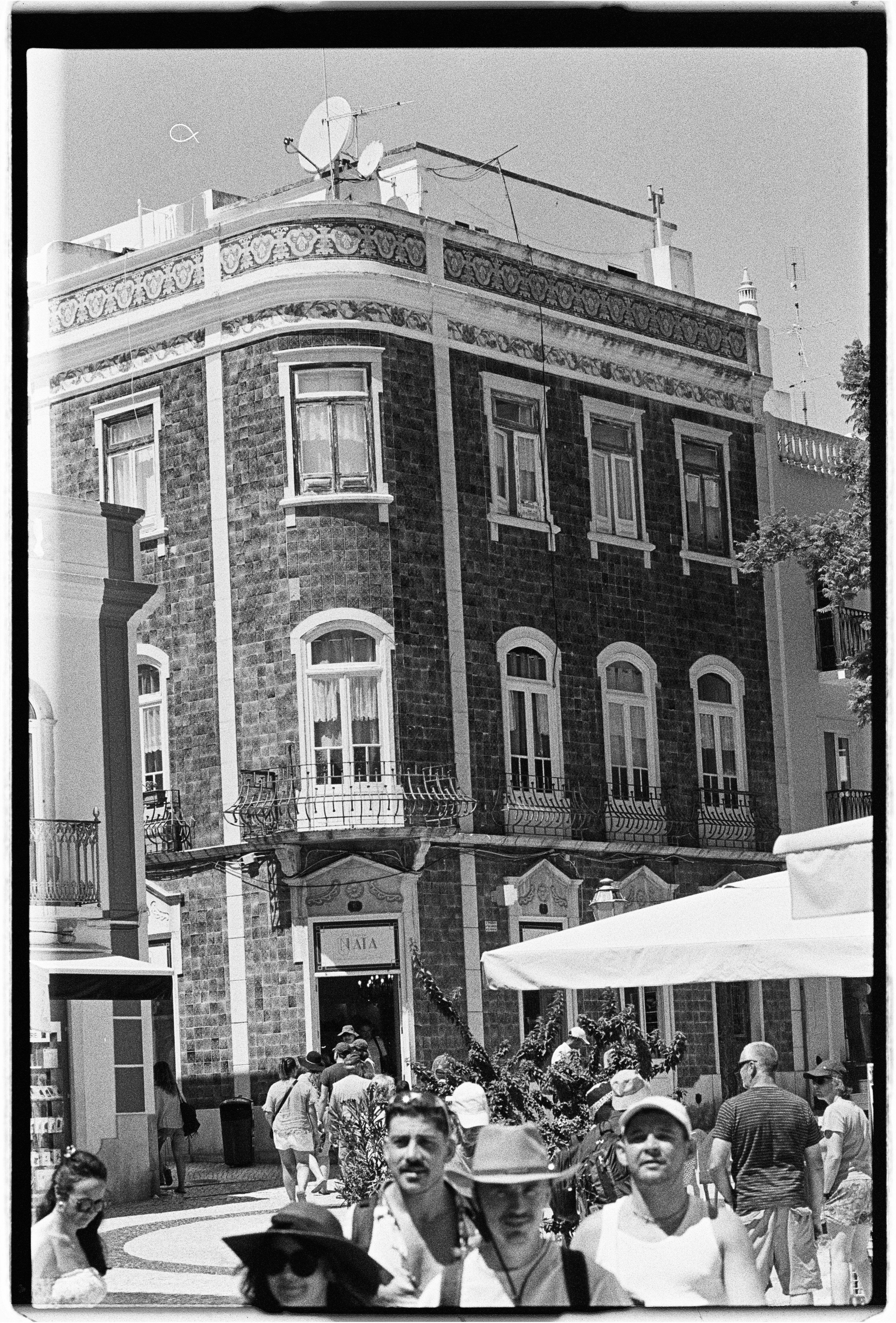 Crowd and ornate corner building in a sunlit plaza