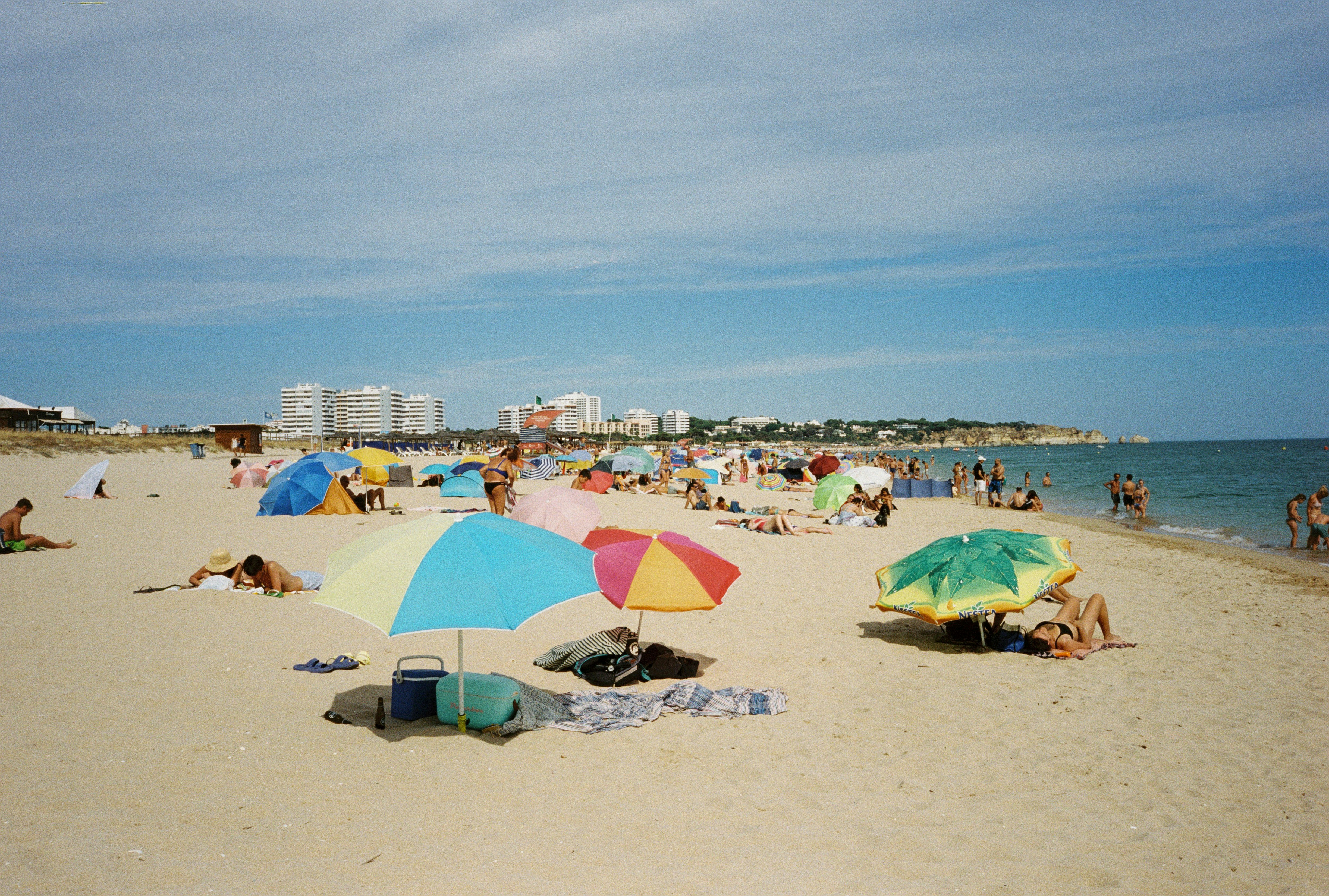 Sunlit Beach Pulse: Colorful Umbrellas Scatter the Shoreline