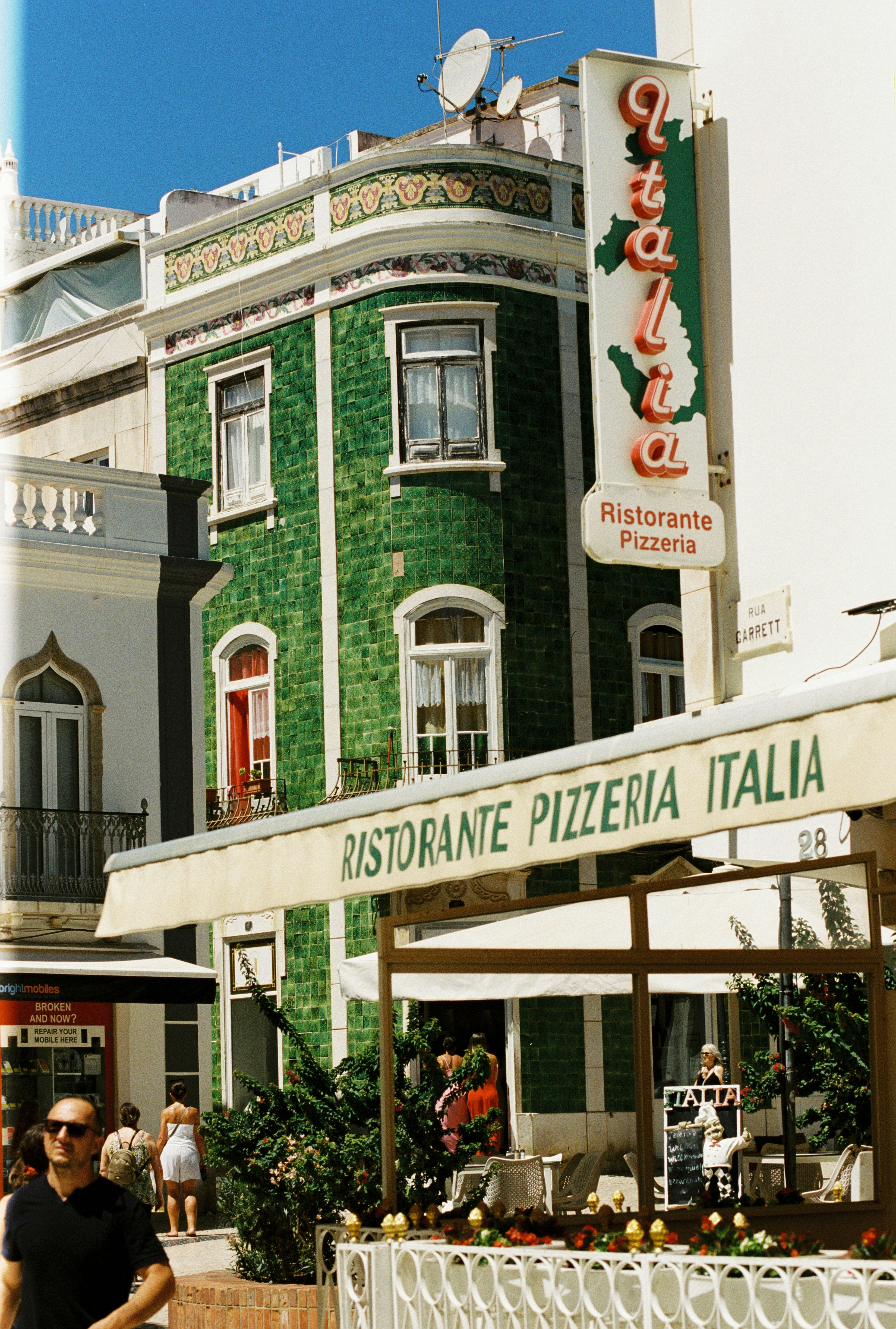 Green Tile Facade and Whimsical Ristorante Signage in Sunlit Italian Street
