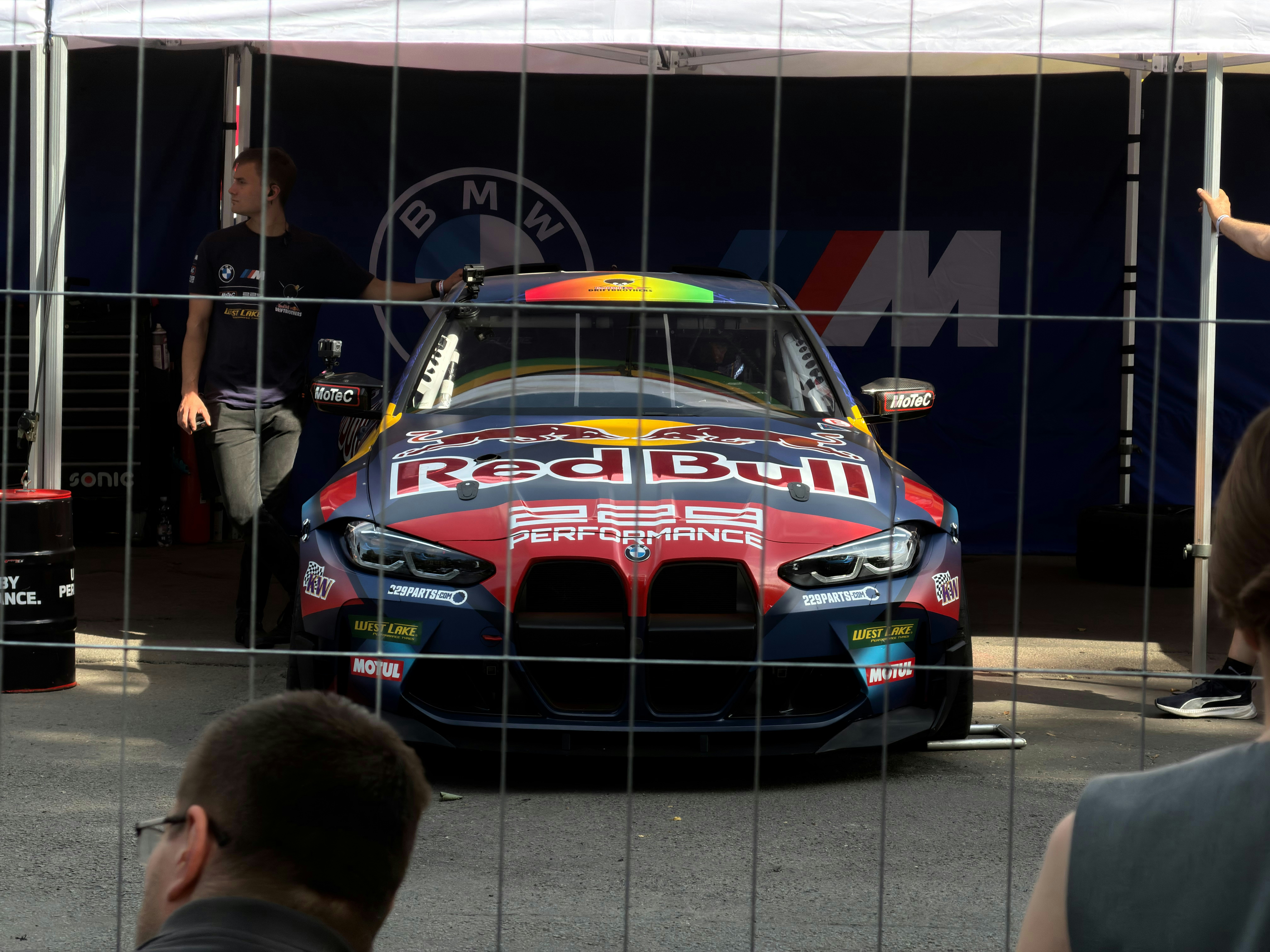 Red Bull BMW Race Car Sealed Behind Grid Fence in Pit Area