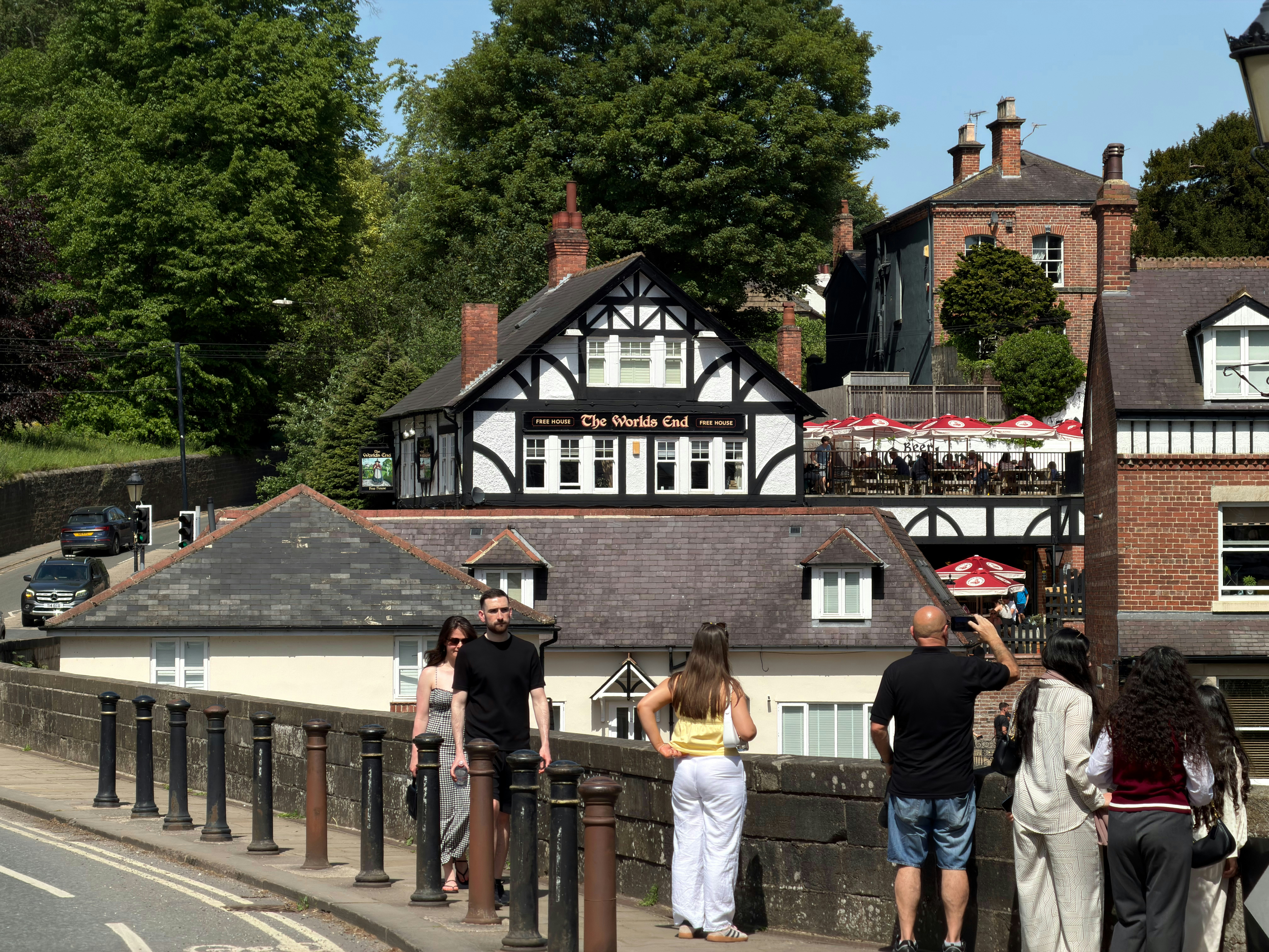 Quaint riverside pub front with tethered pedestrians and Tudor-style inn