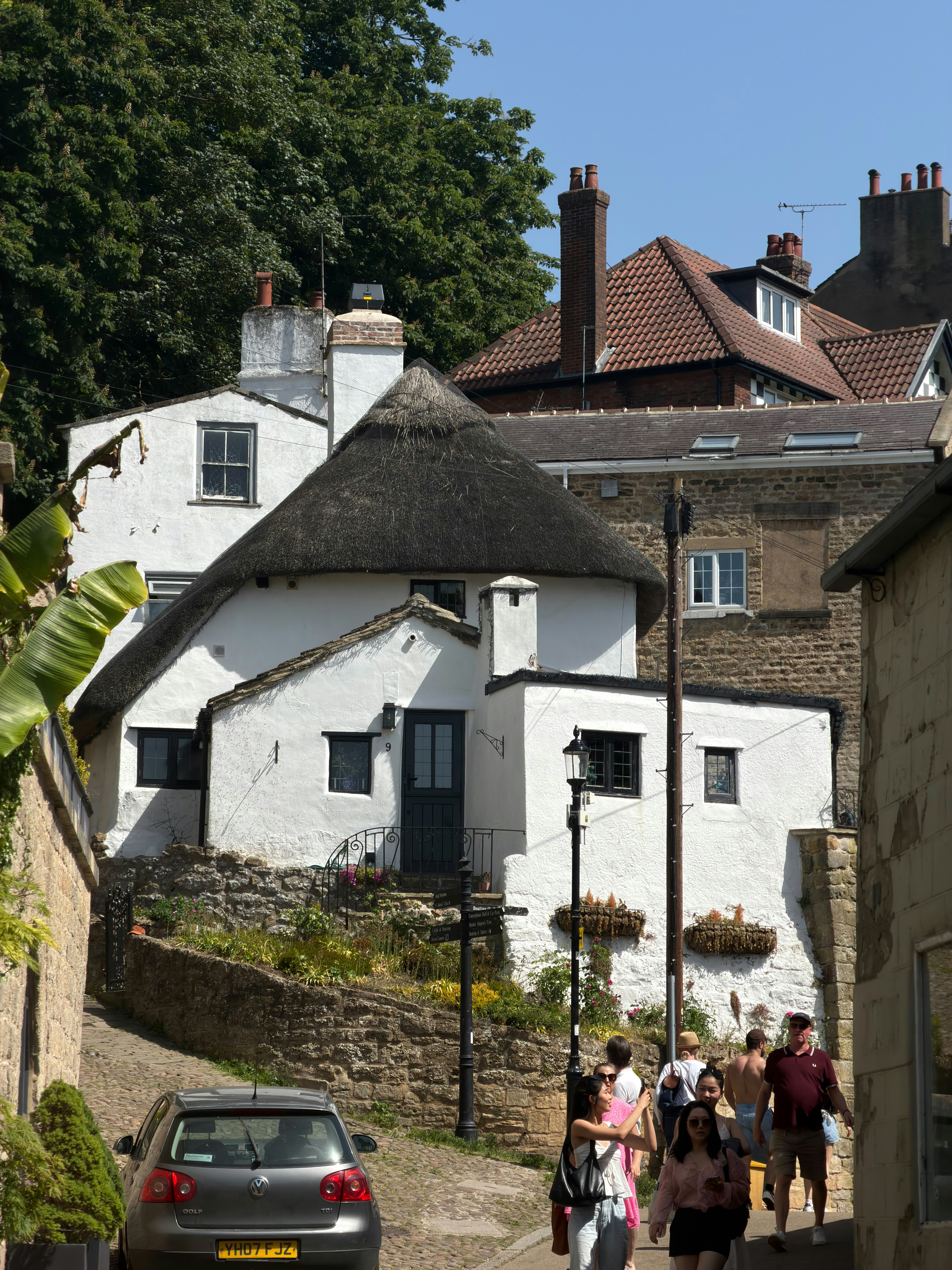 White-washed Cottage with Thatched Roof Under a Sky of Chimneys