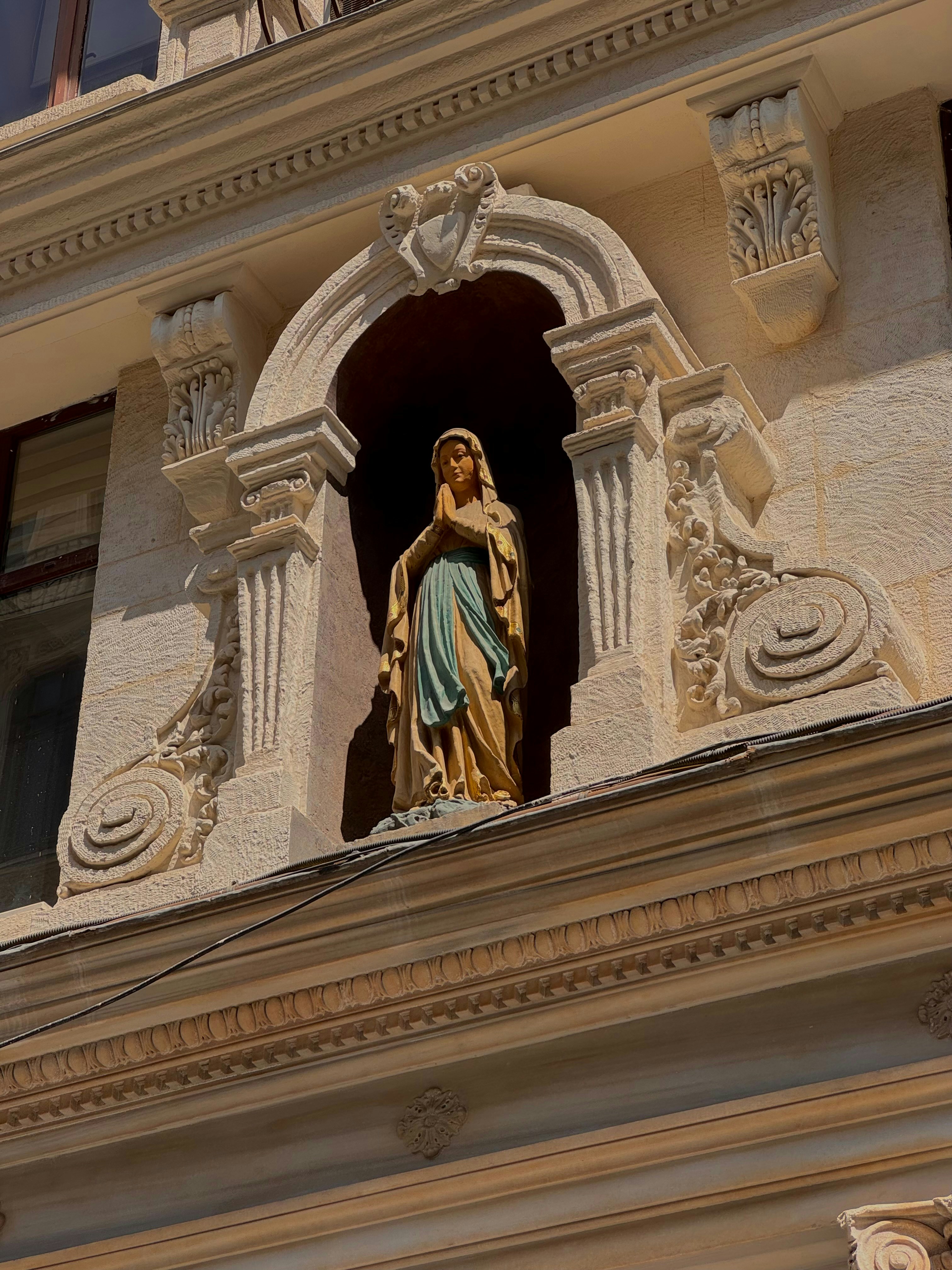 Statue Shrine in Carved Archway Over a Sunlit Facade