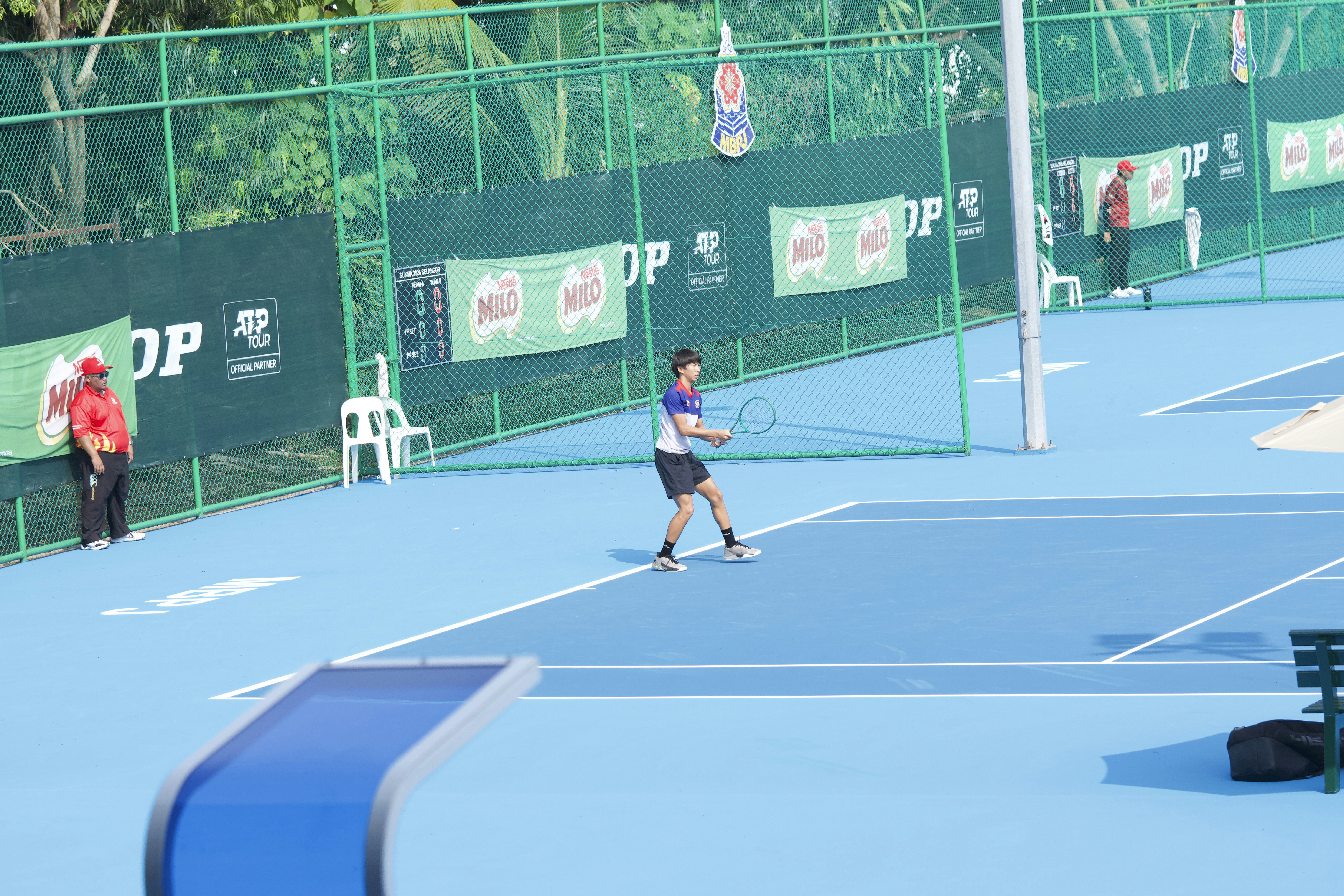 Mid-Court Return: A Young Player Stays Ready on a Bright Blue Tennis Court