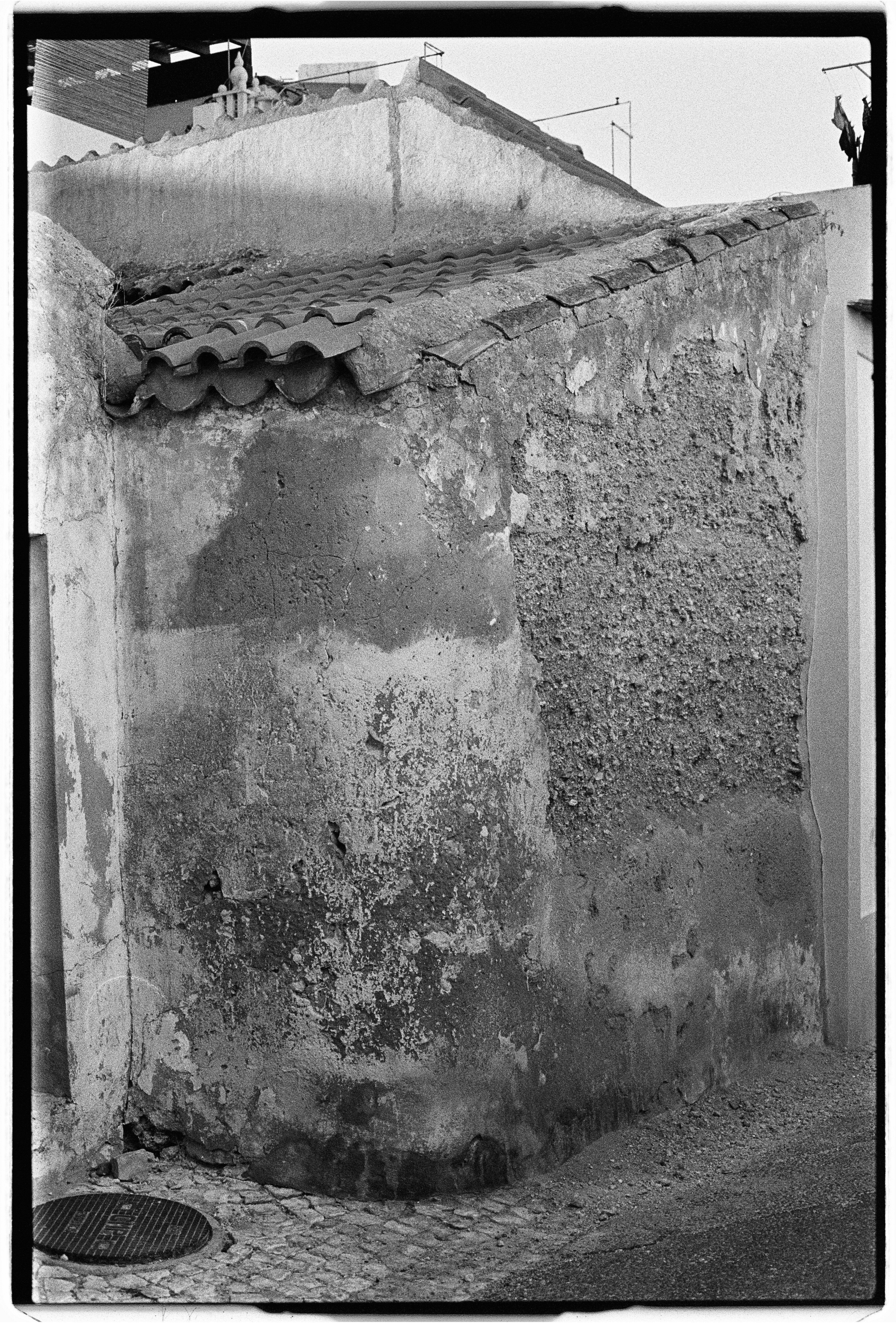 Weathered Corner: Crumbling Wall Under Tile Roof