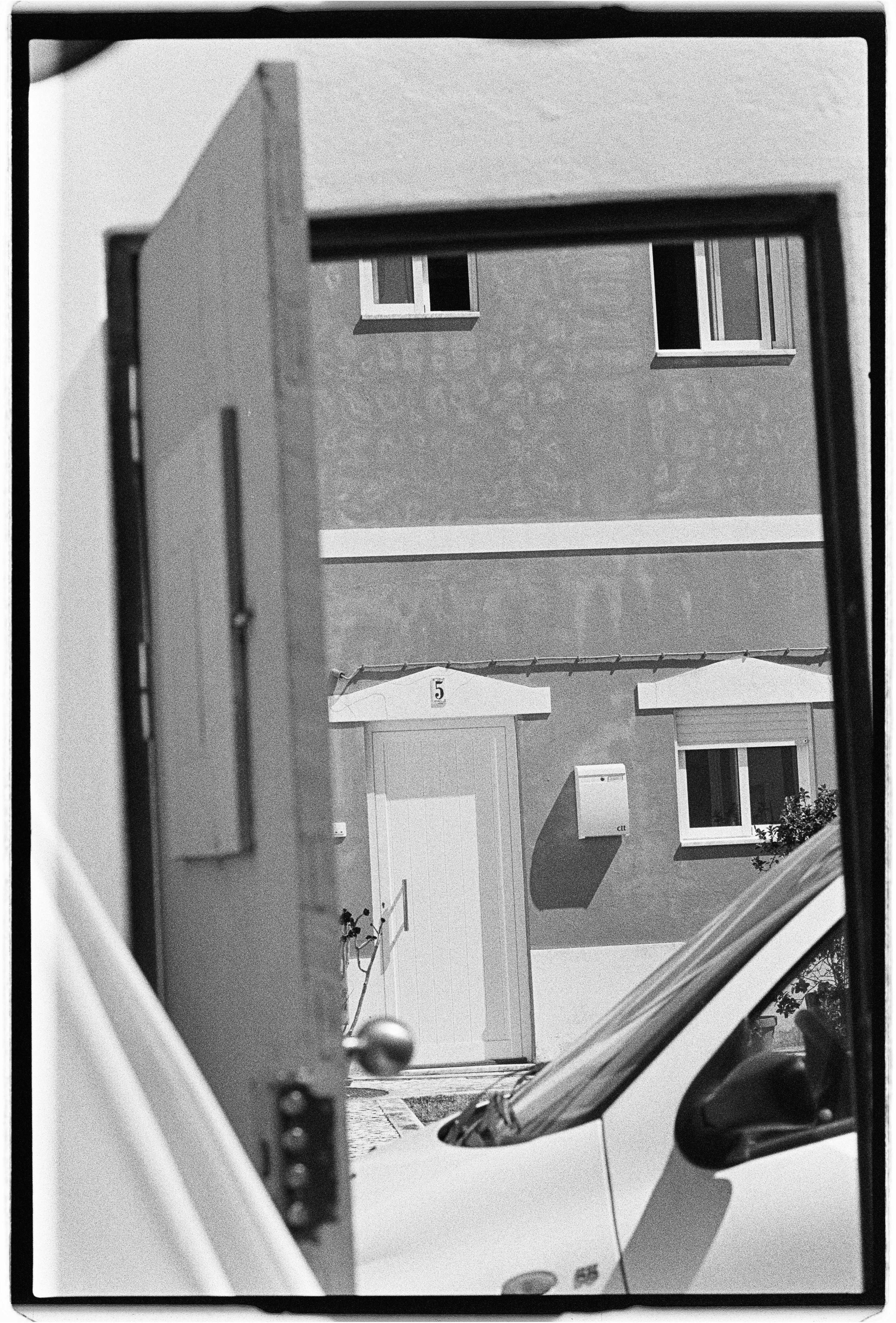 Through the Doorway: A Quiet Streetframed by a Car