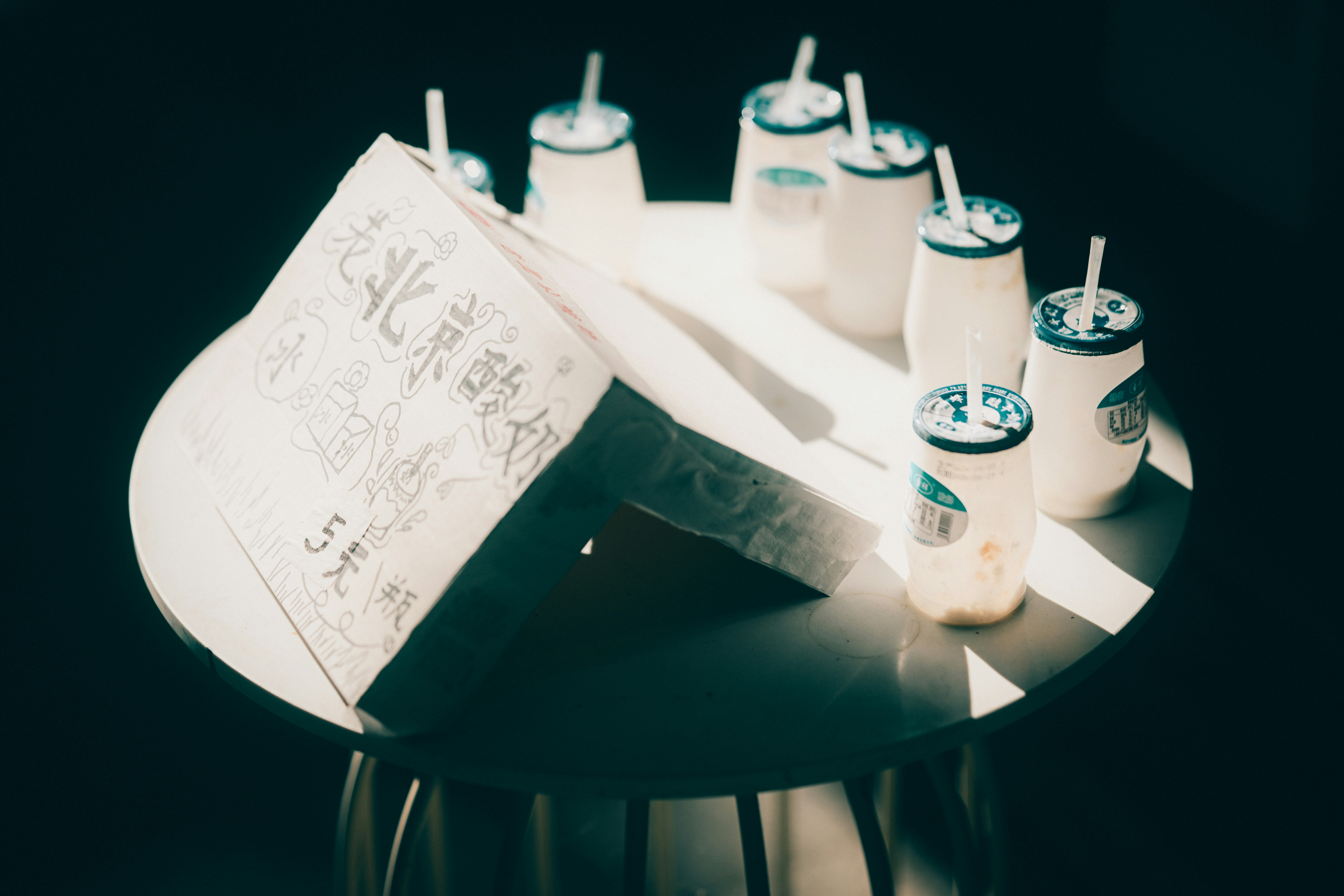 Cardboard milkshakes on a sunlit patio, tilted toward an illustrated carton