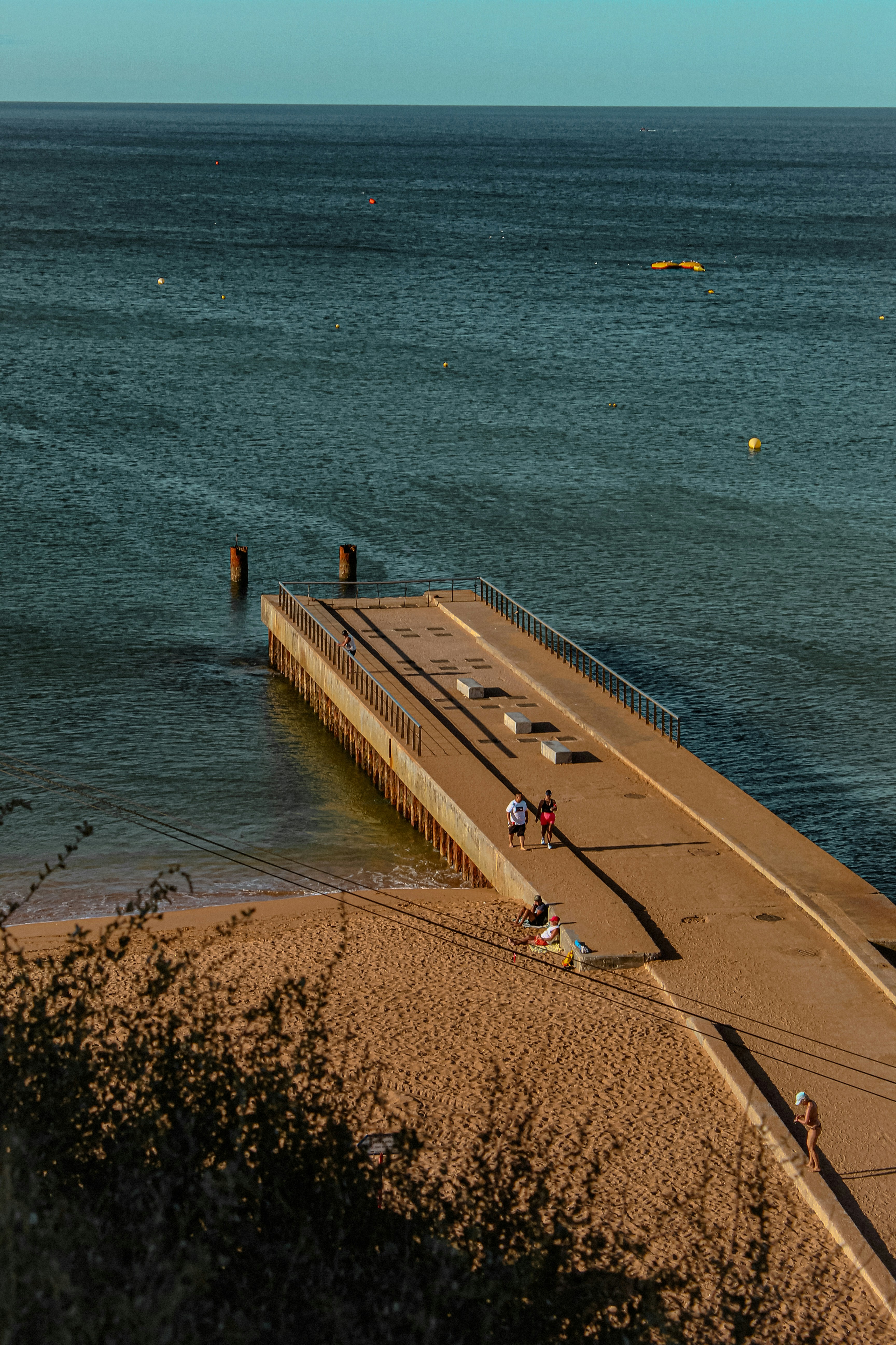 Pier Under Warm Coastal Light: People Stroll the Channelized Path