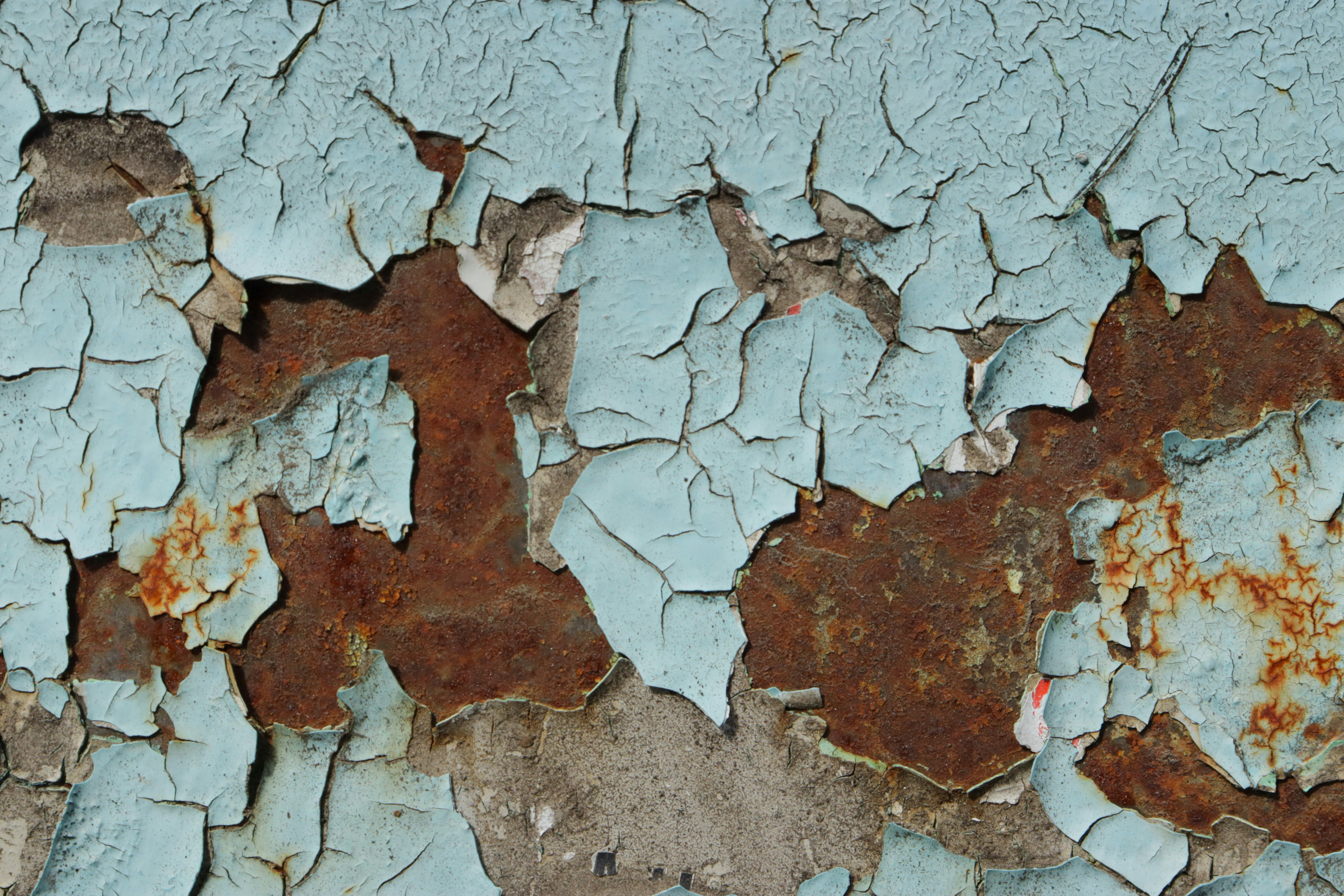 Weathered Teal and Rust: Cracked Paint on a Textured Wall