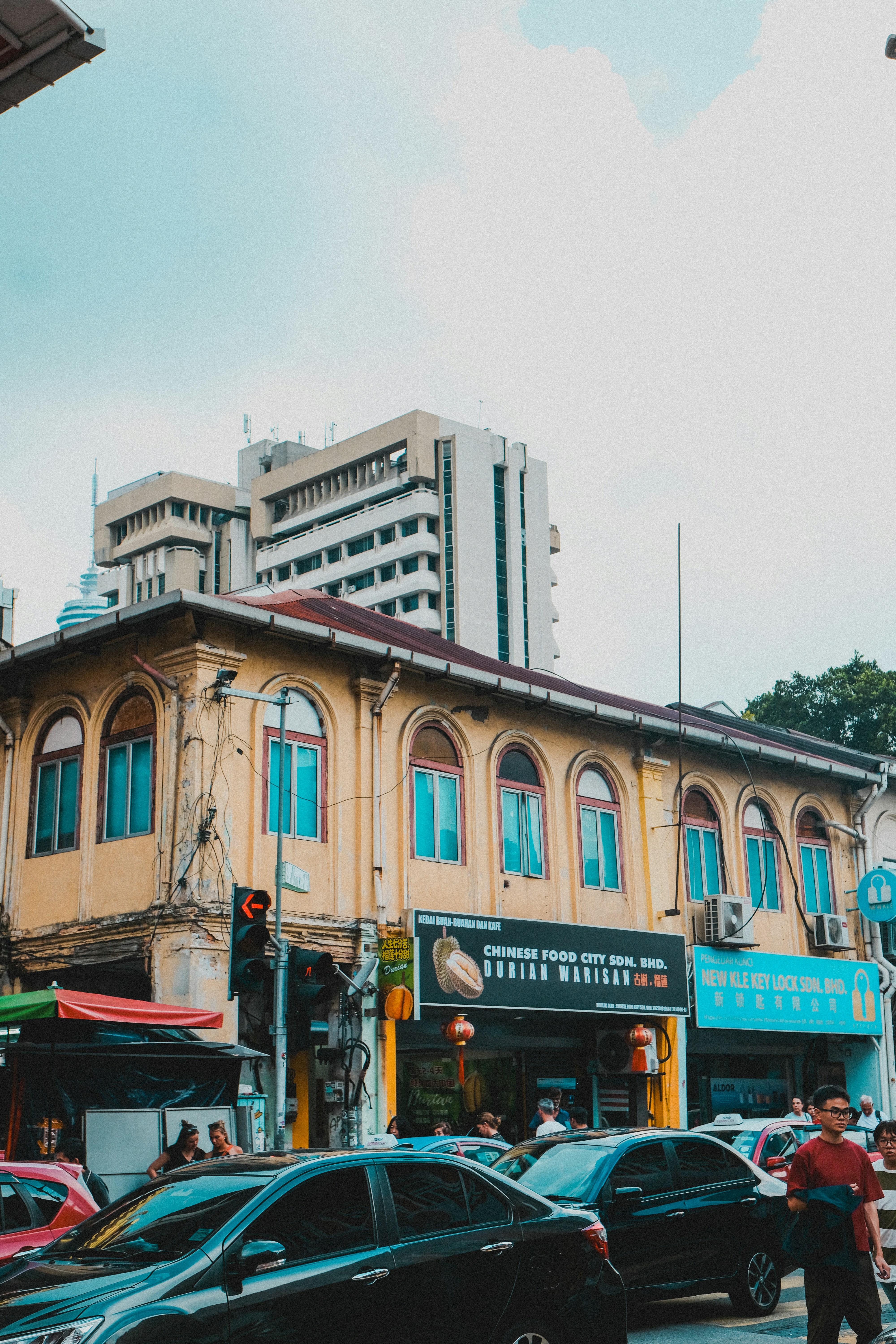 Sunlit Chinatown Facade: Orange Walls, Turquoise Windows, and Urban Motion