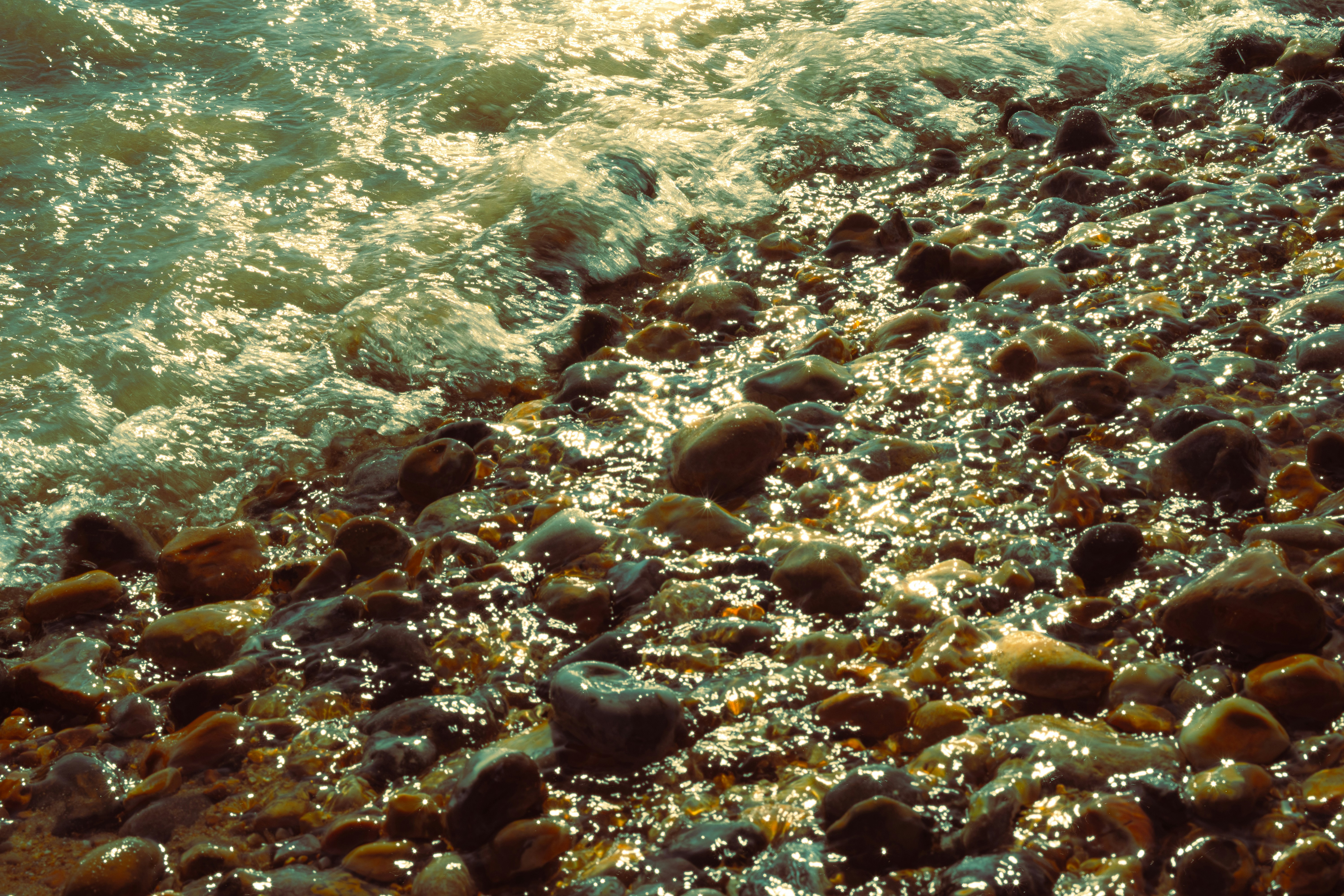 Sunlit Pebbles by the Sea: Light, Texture, and Quiet Ripples