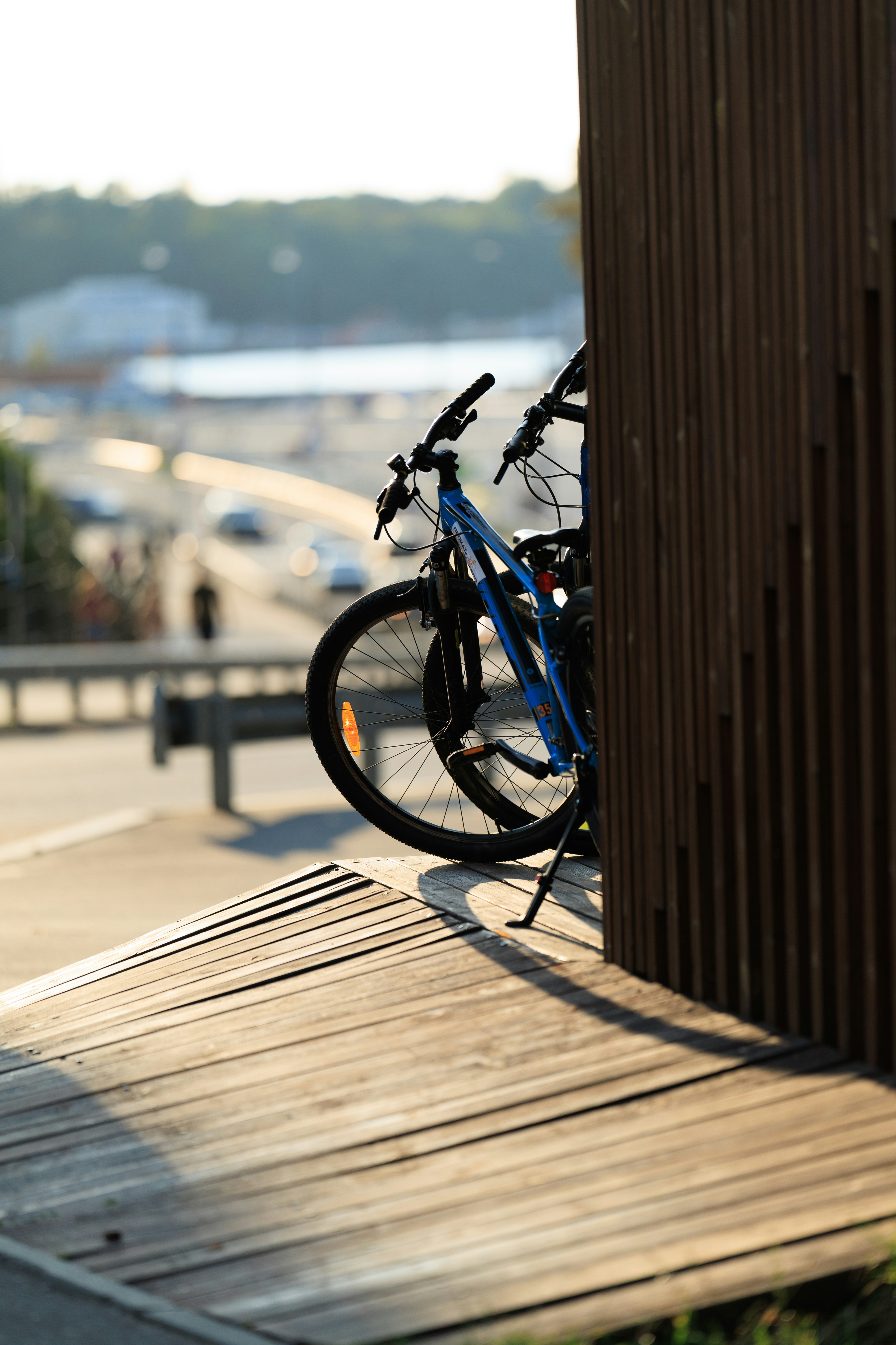 Blue bicycle tucked beside a wooden railing on a sunlit boardwalk