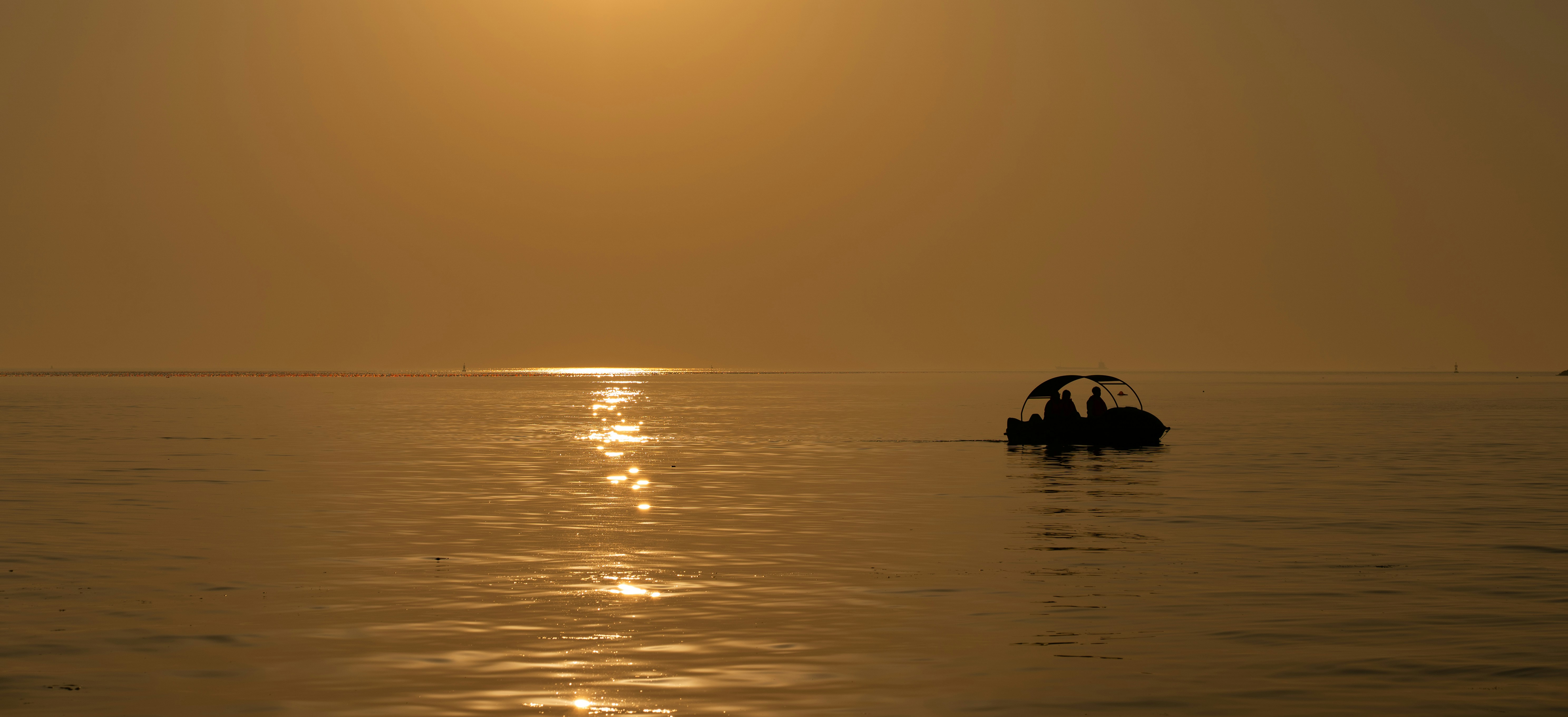 Silhouette at Waterline: A lonely boat in golden hush