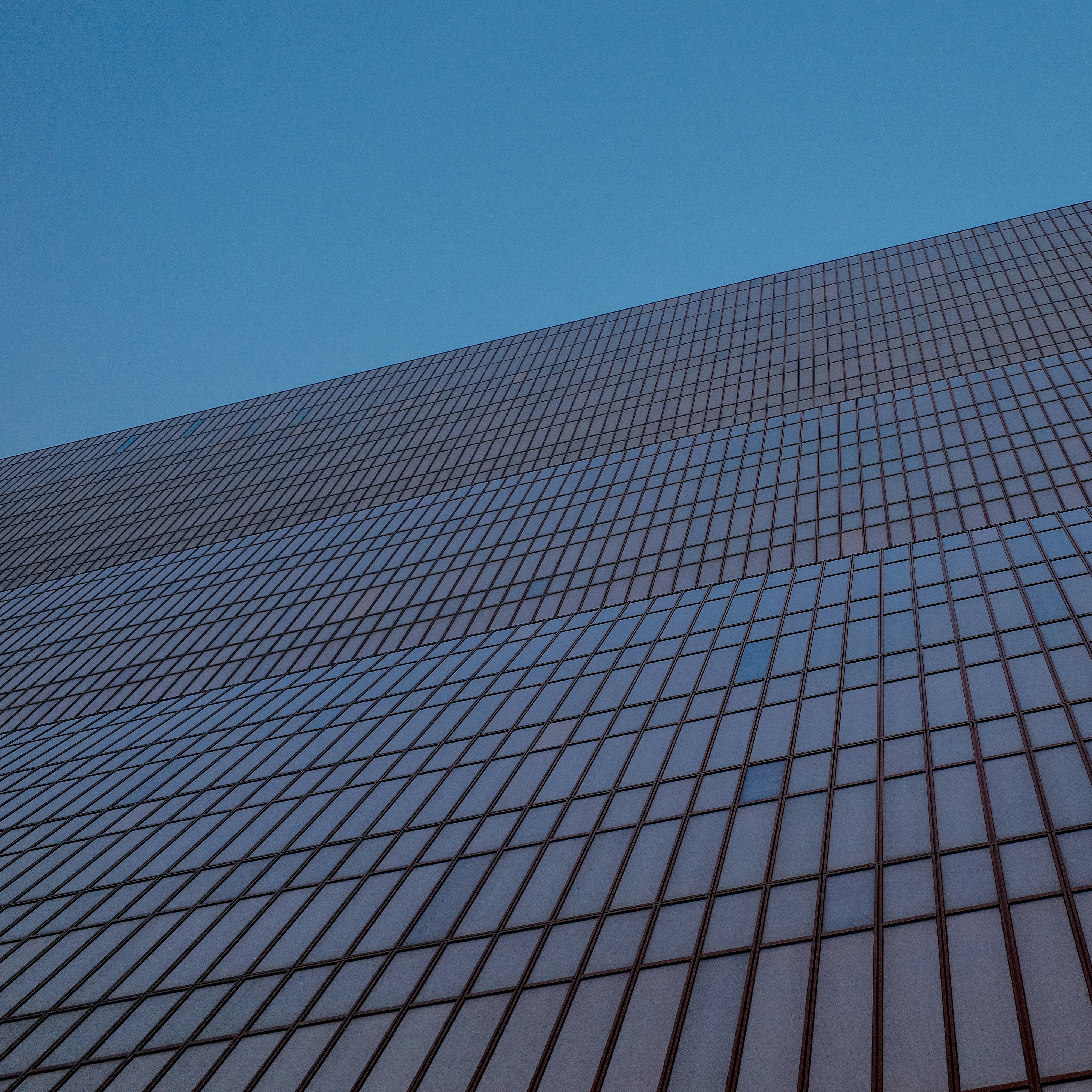 Tilted Facade: A Grid of Glass and Sky