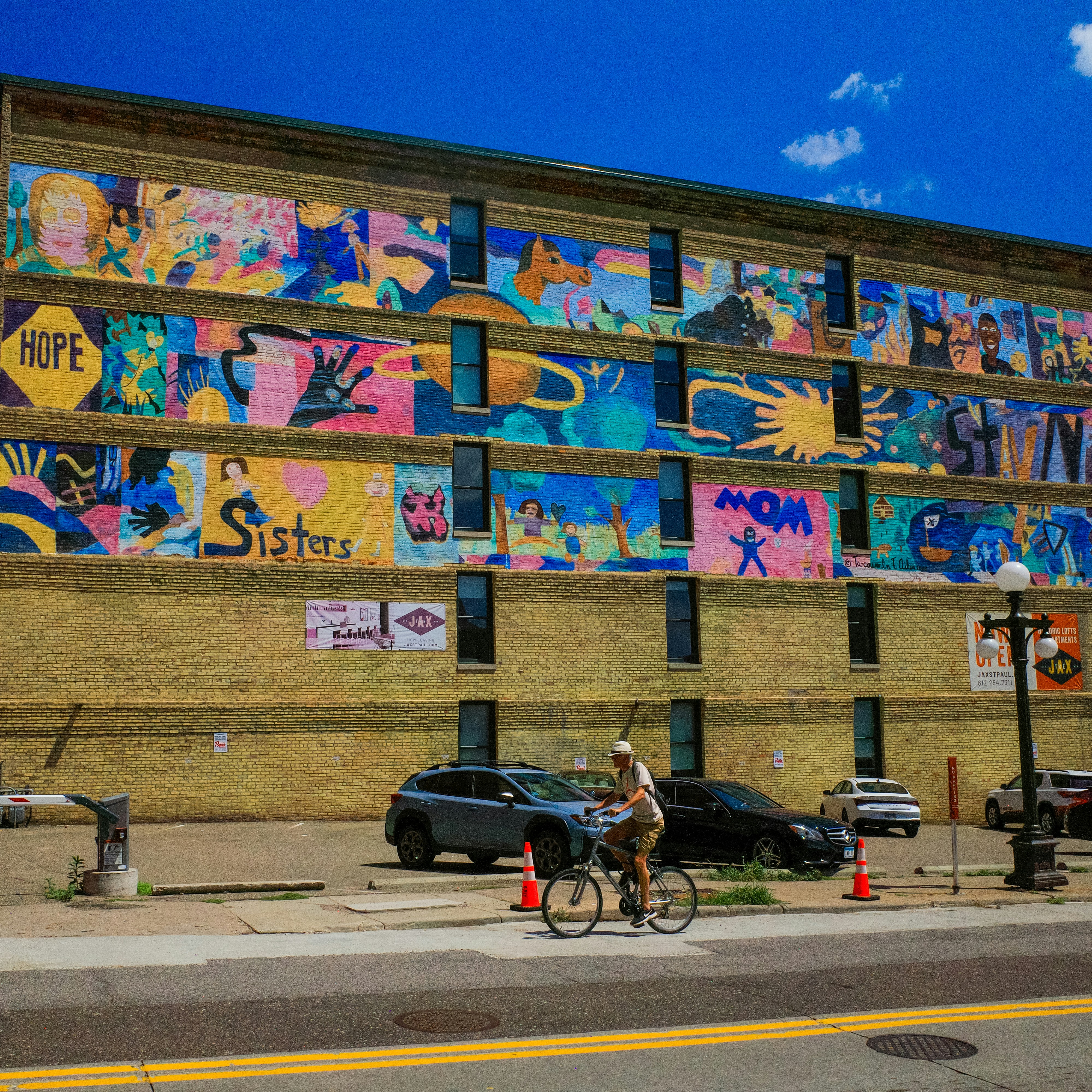 Colorful mural over brick building with cyclist in foreground
