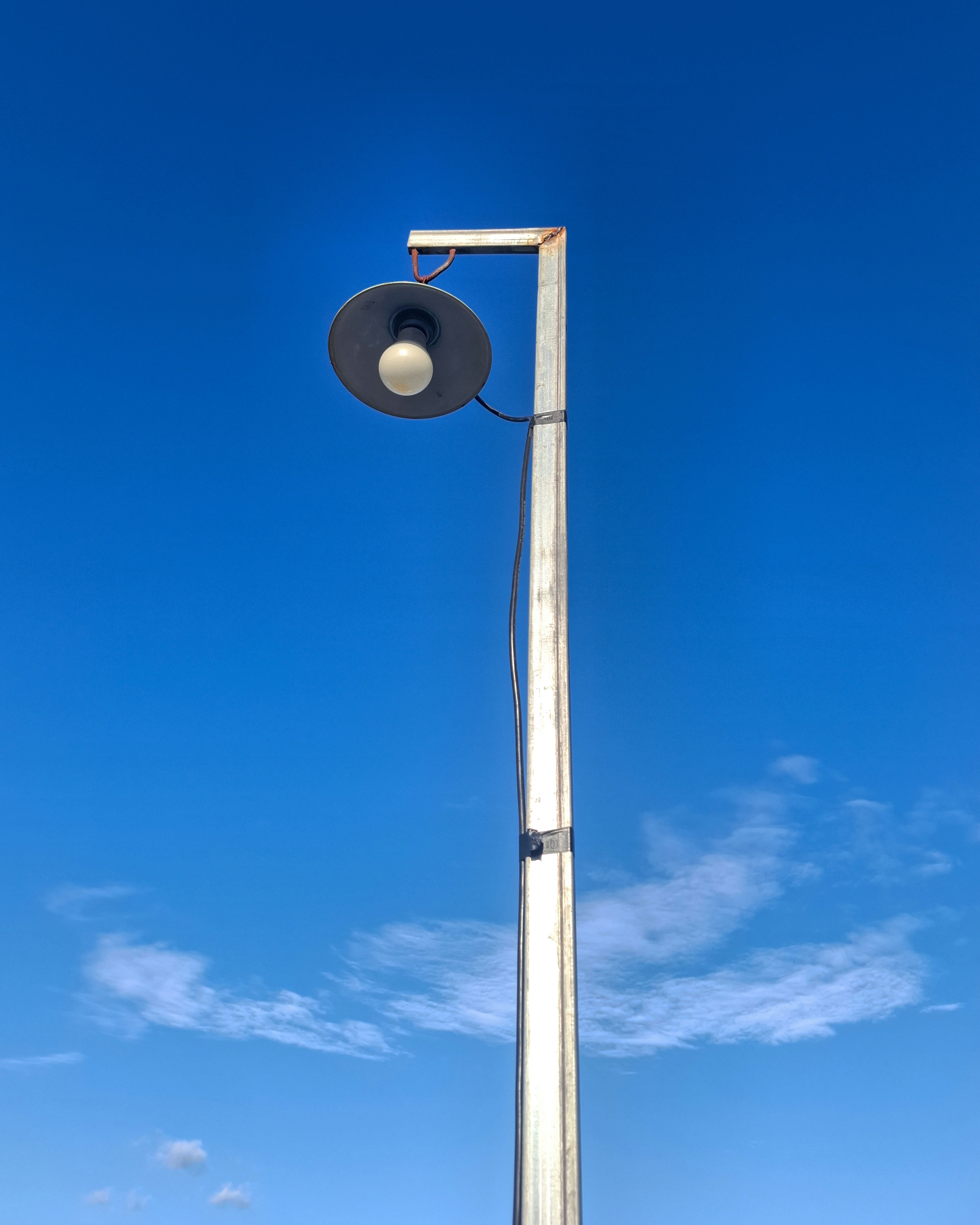 Pole Star: A Lone Streetlamp Rises Against a Clear Blue Sky
