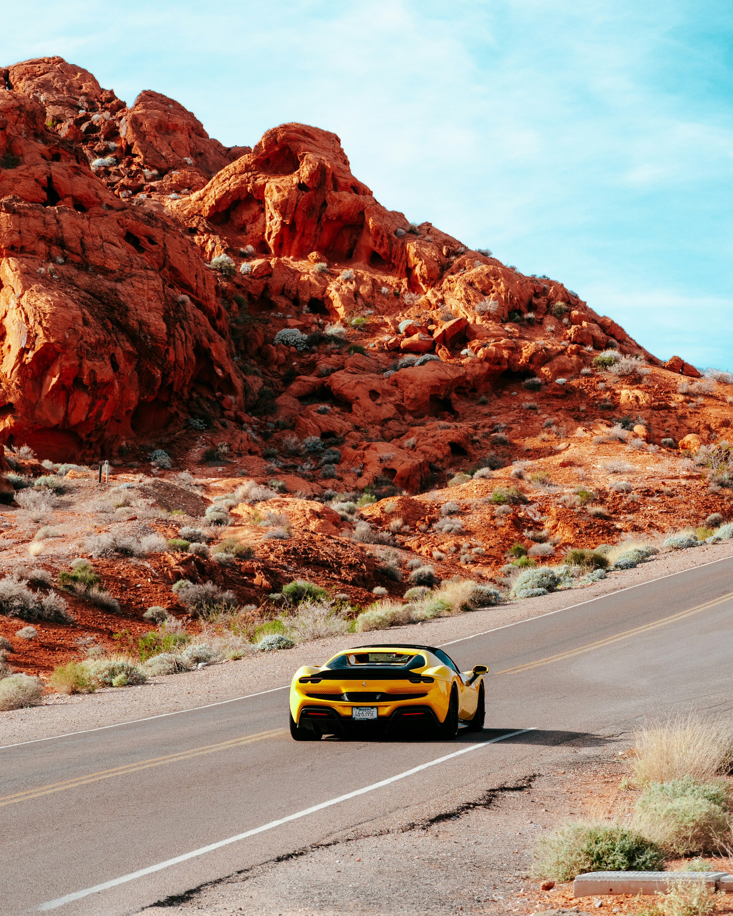 Yellow Sports Car Carves the Desert Road beneath Crimson Cliffs