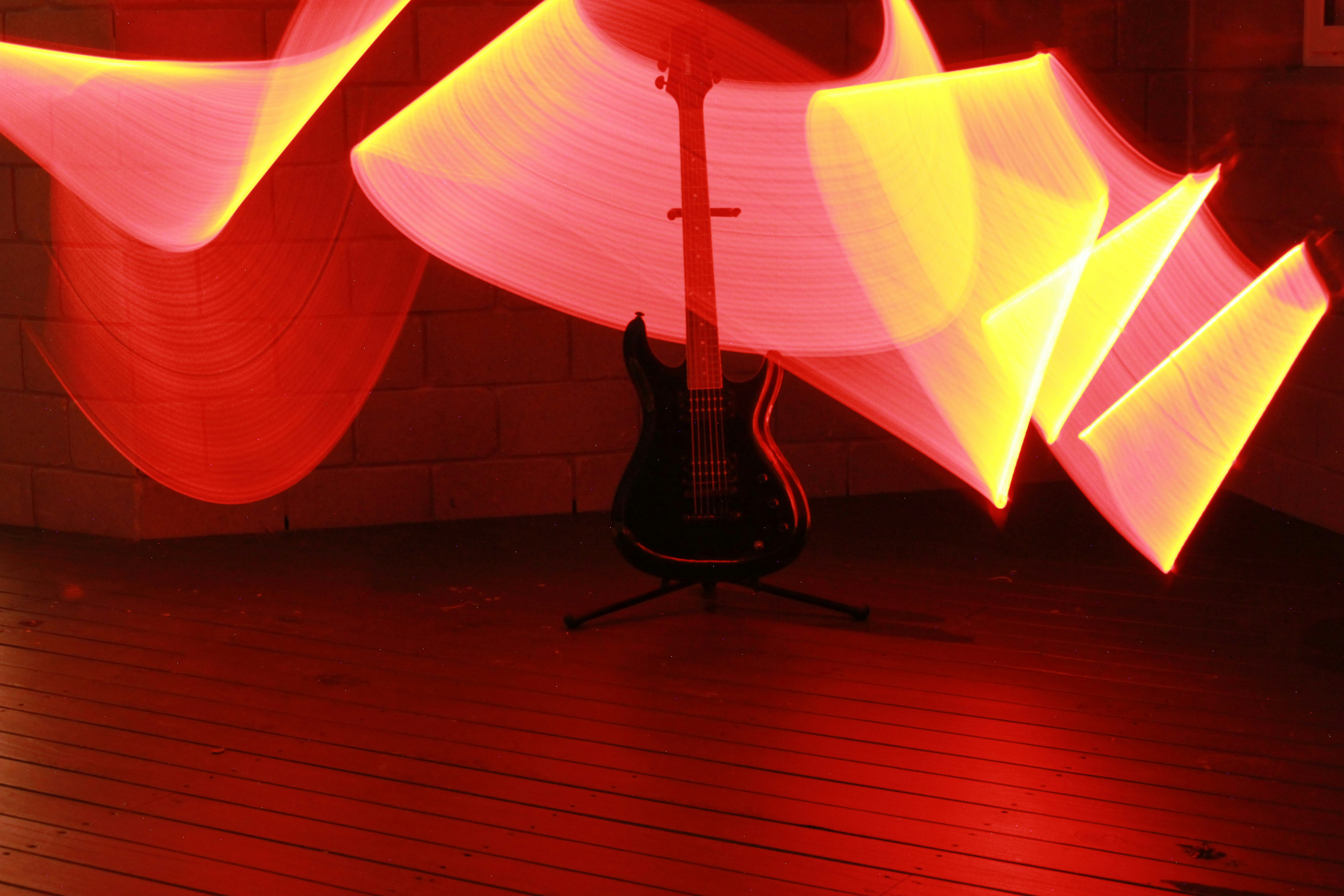 Low-wooded Stage: A Red-Hued Guitar Amidst Moving Light Trails