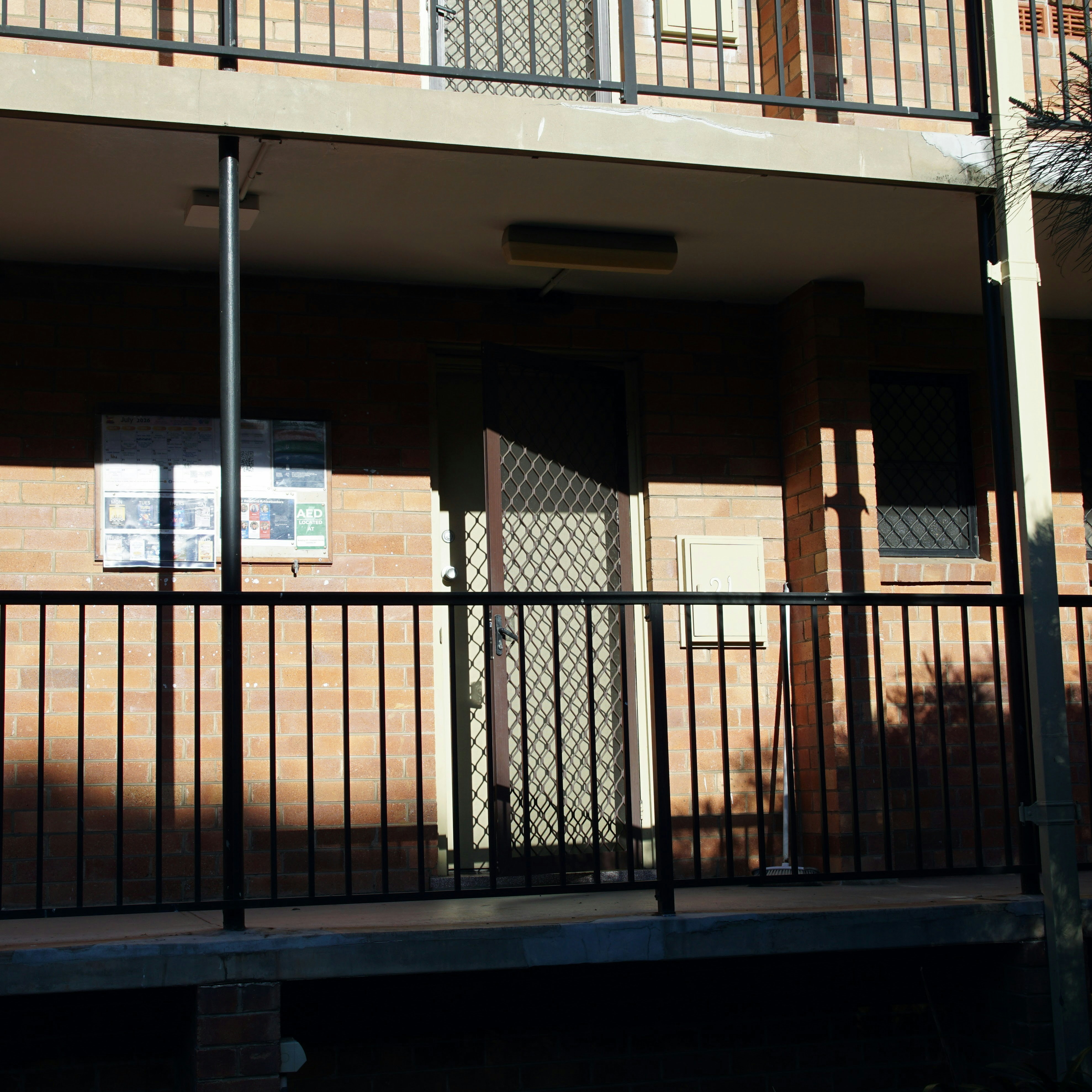 Brick Apartment Doorway Under Shadowed Balcony