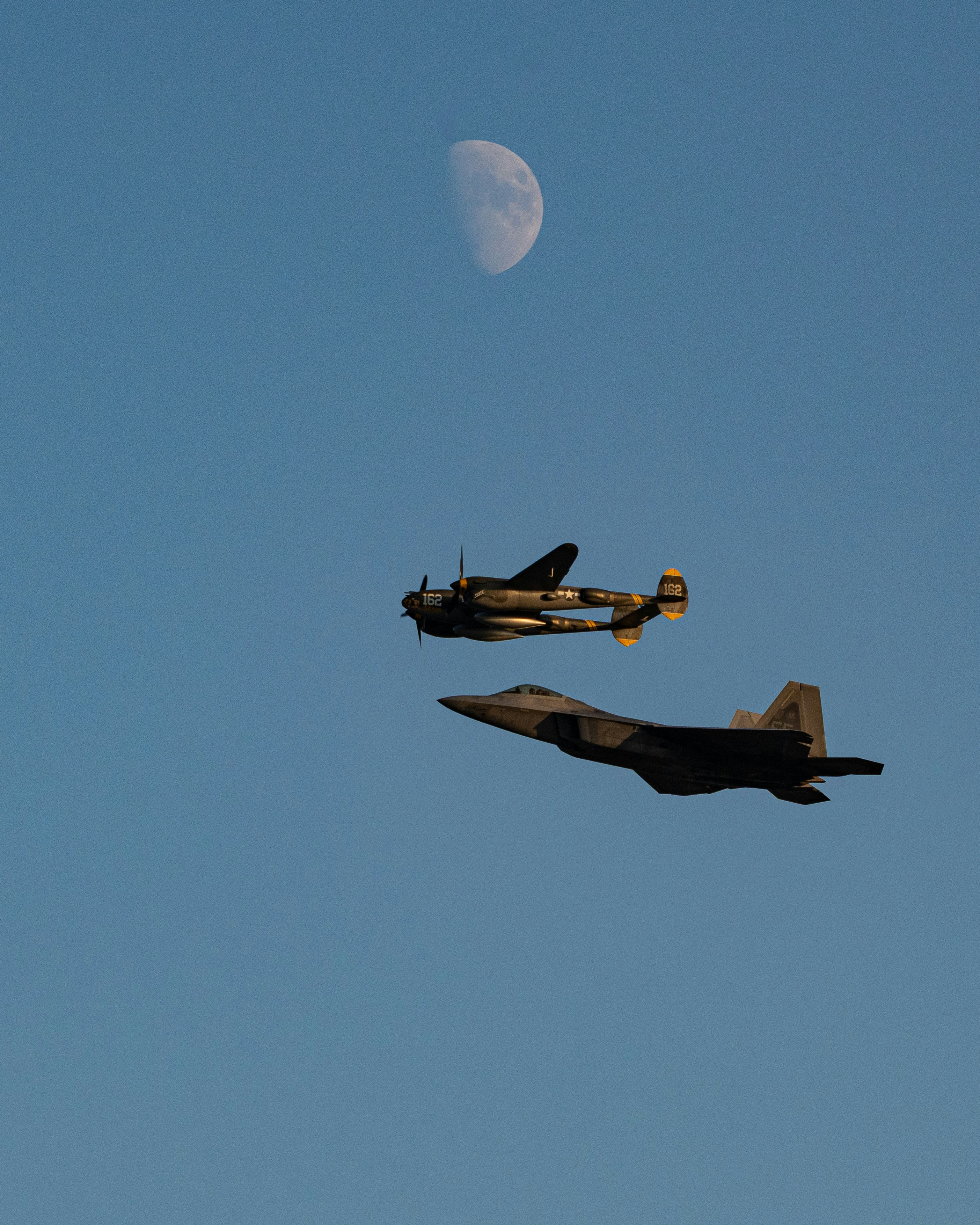 Midair Convergence: A WWII Trainer and an F-22 Shadow the Moon