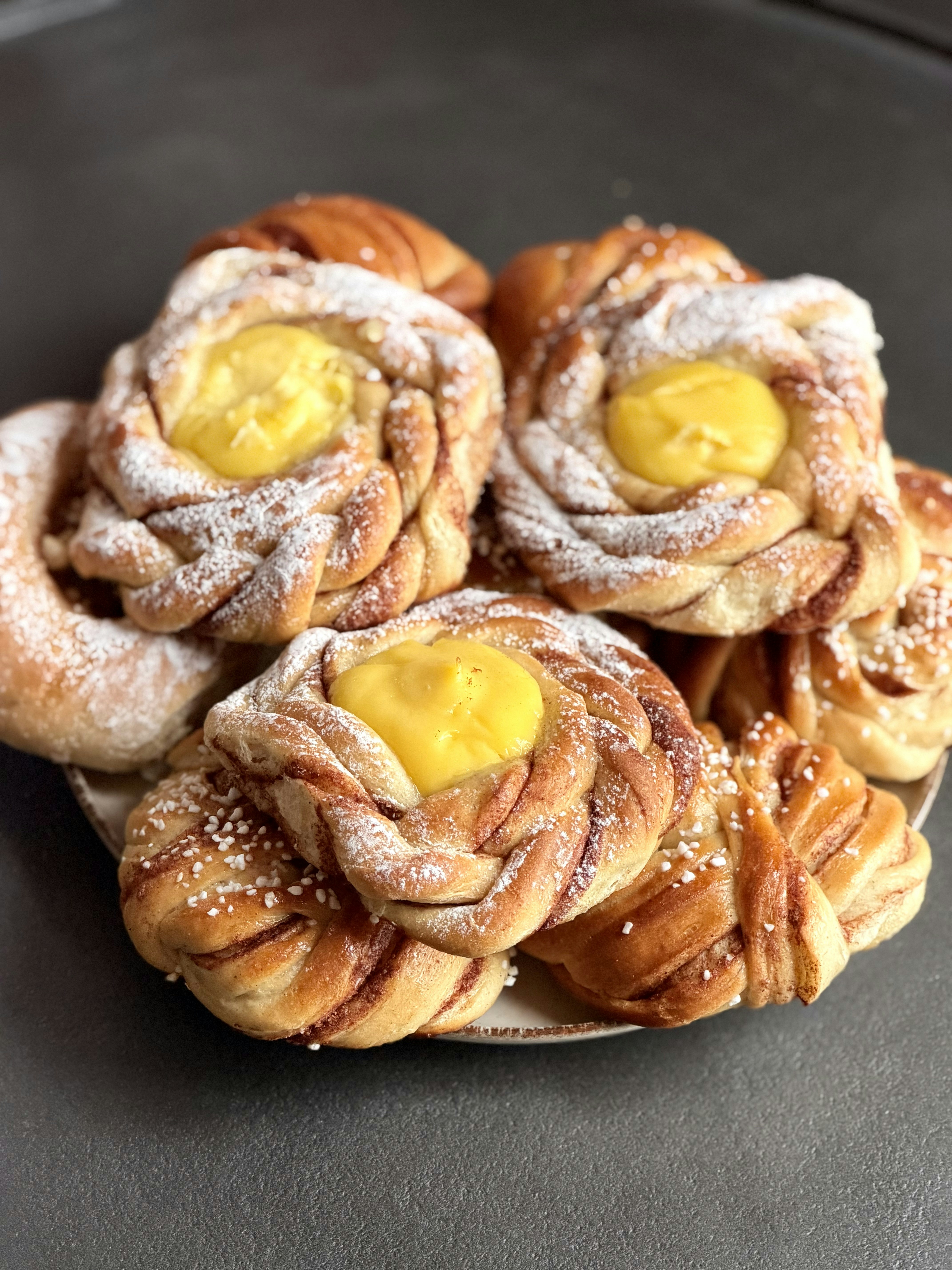 Dainty Swirls: Cream-Filled Danish Star Clusters on a Dark Plate