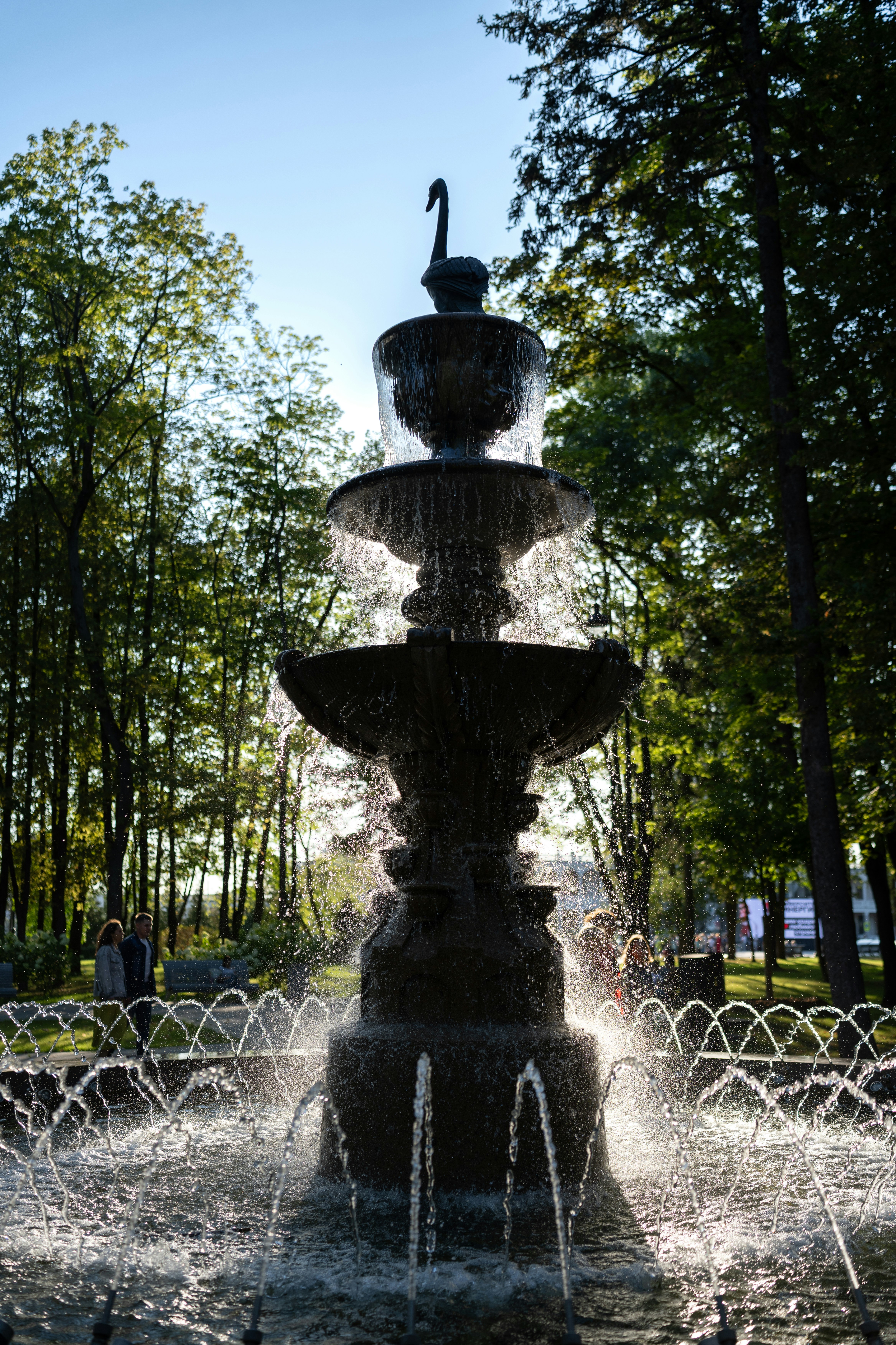 Echoes of Water and Stone: A Tiered Fountain Framed by Tall Shadows