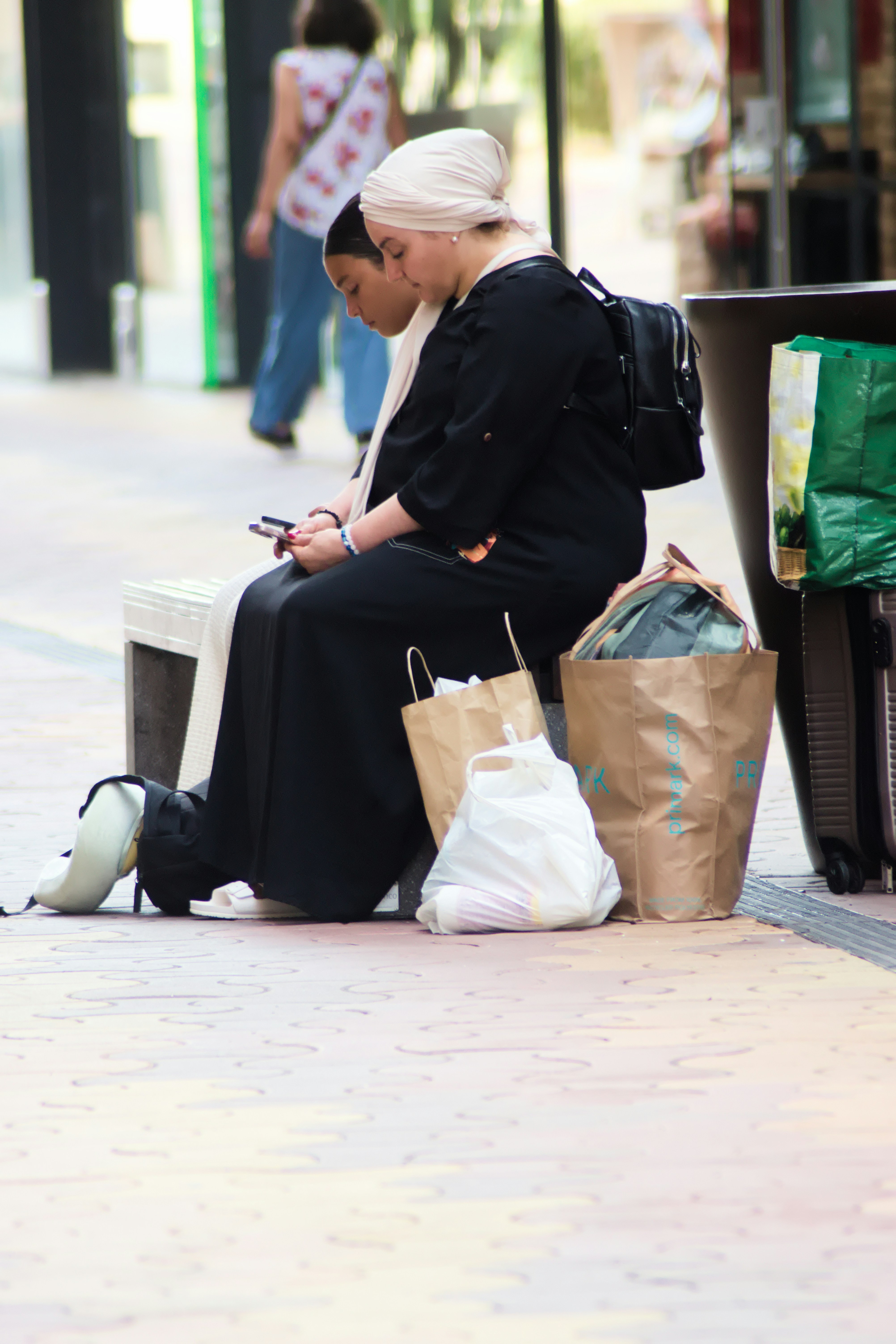 Crossing Quiet Moments: A scarfed companion scrolling on a bench
