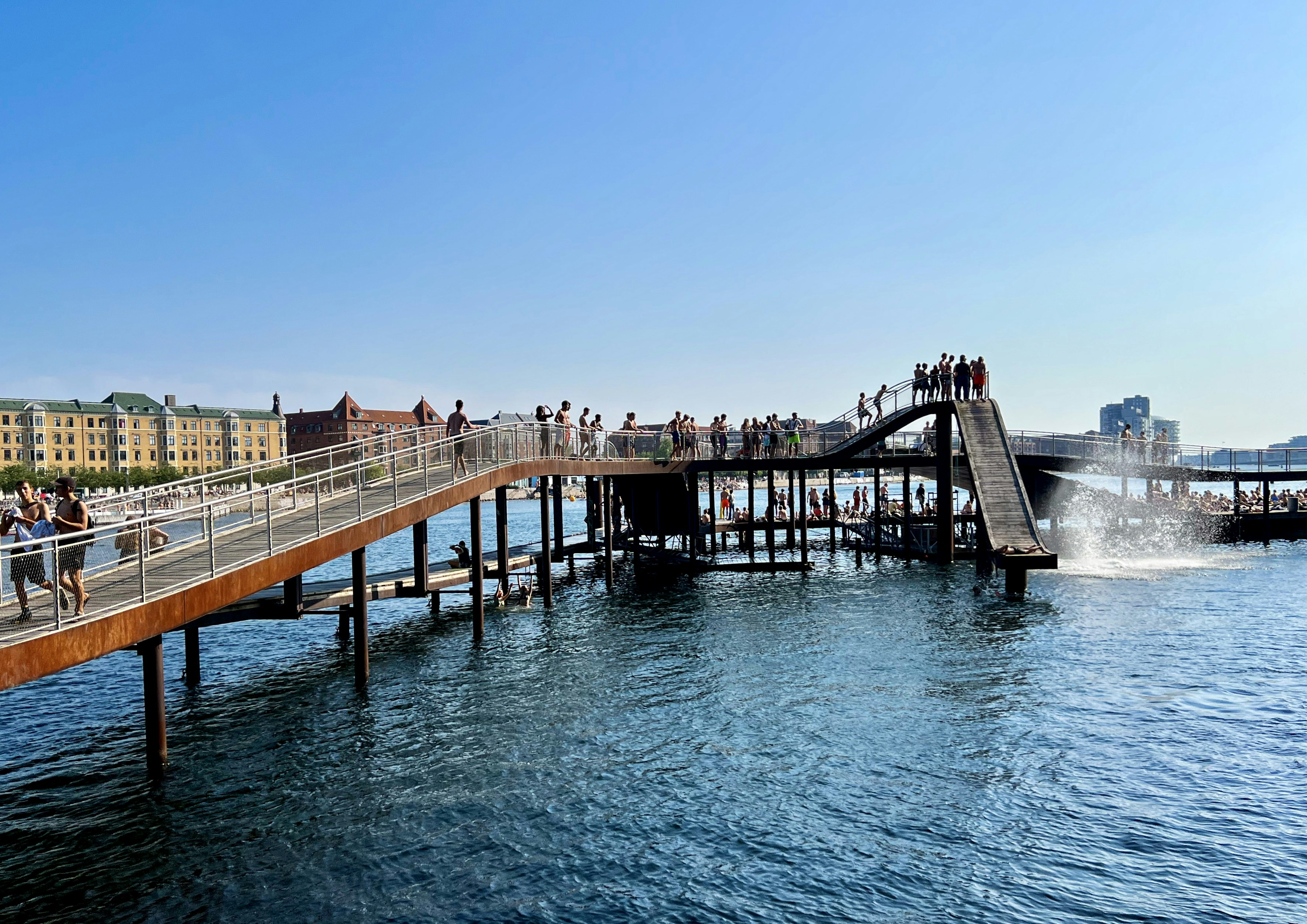 Gliding Horizon: People Trek Across a Waterfront Pier
