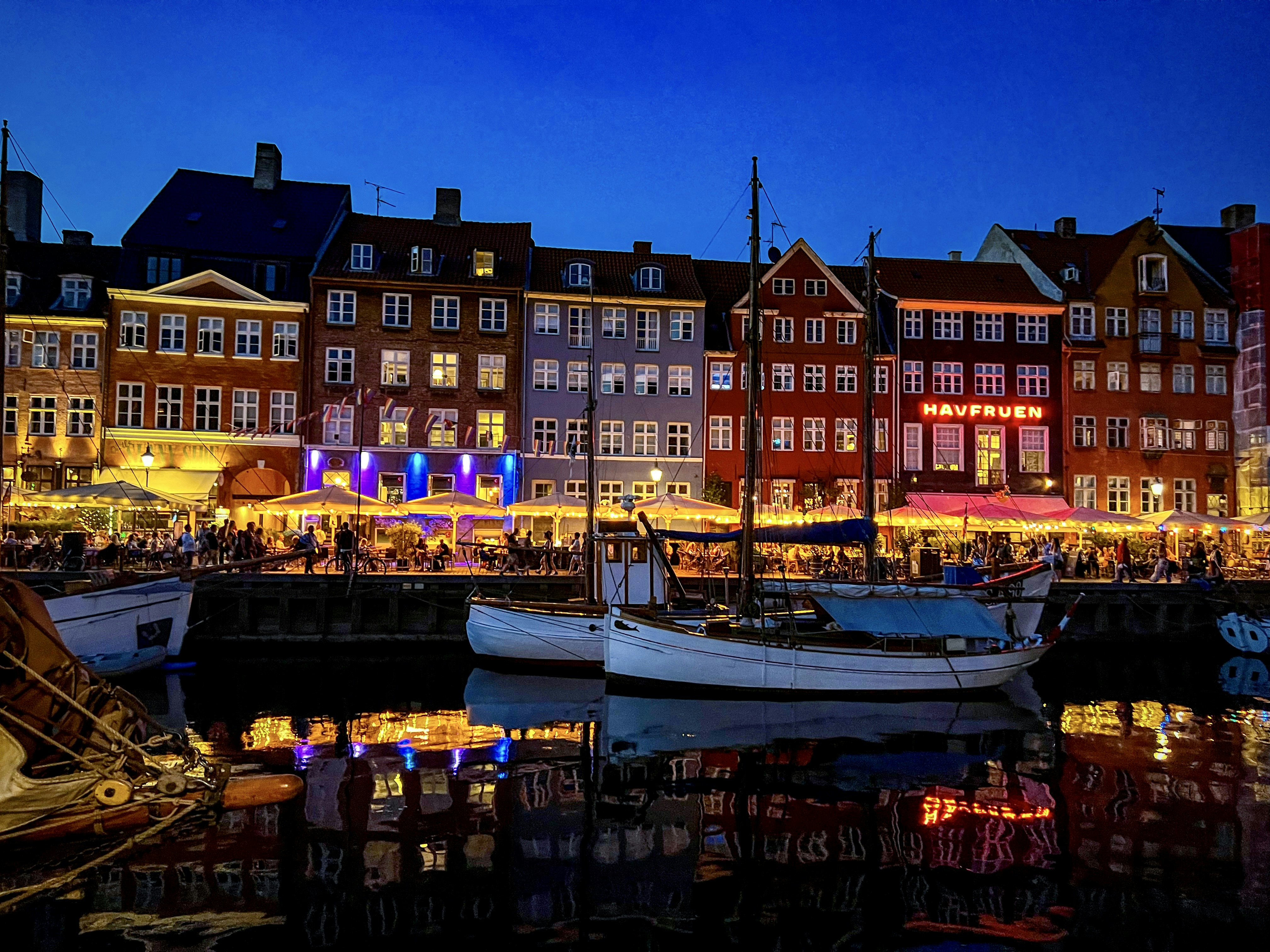Colorful Waterfront at Dusk: Boats, Reflections, and Lanterns