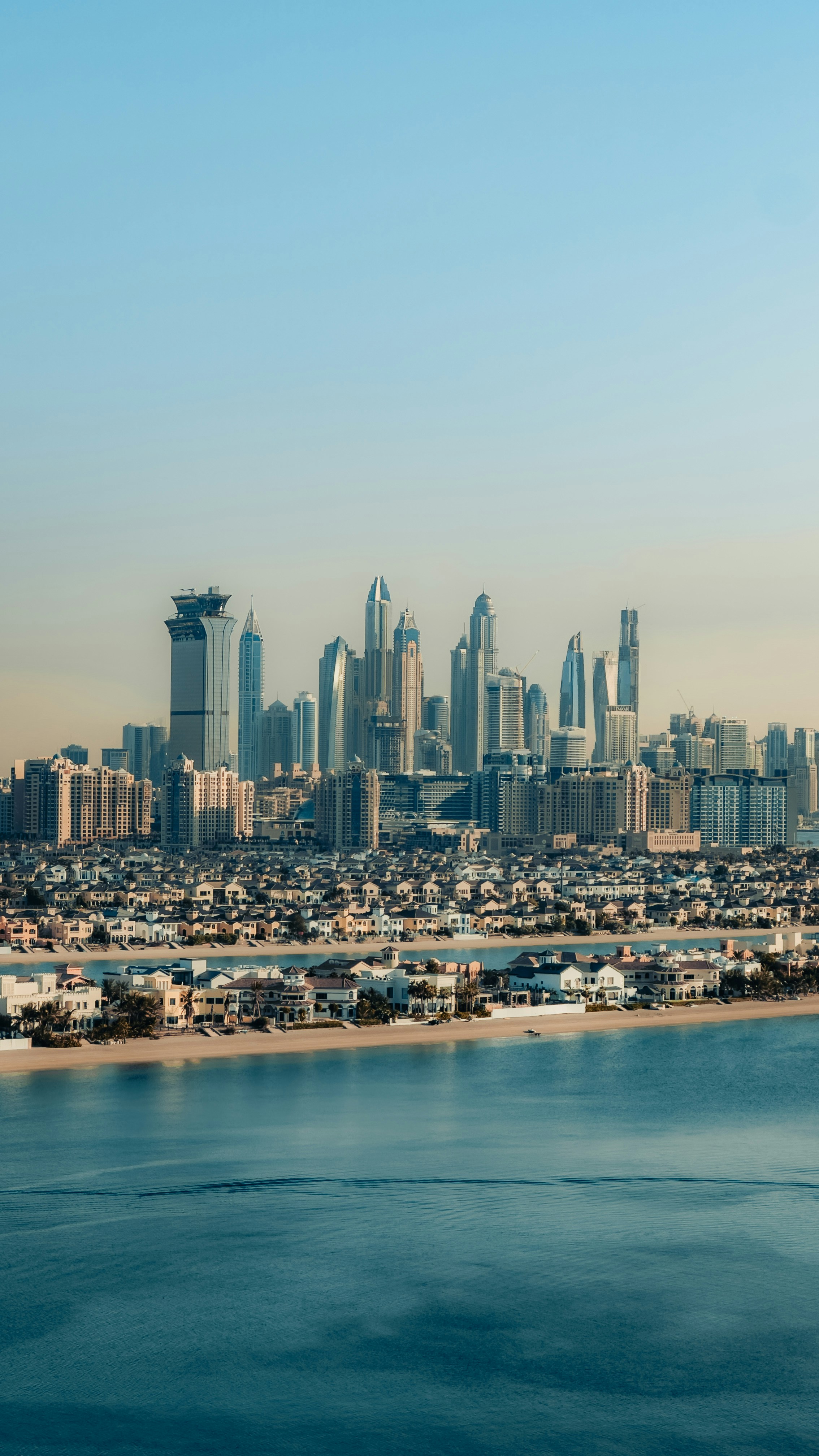 Sunlit Metropolis: Coastal Skyscrapers Rise Beyond Quiet Shores