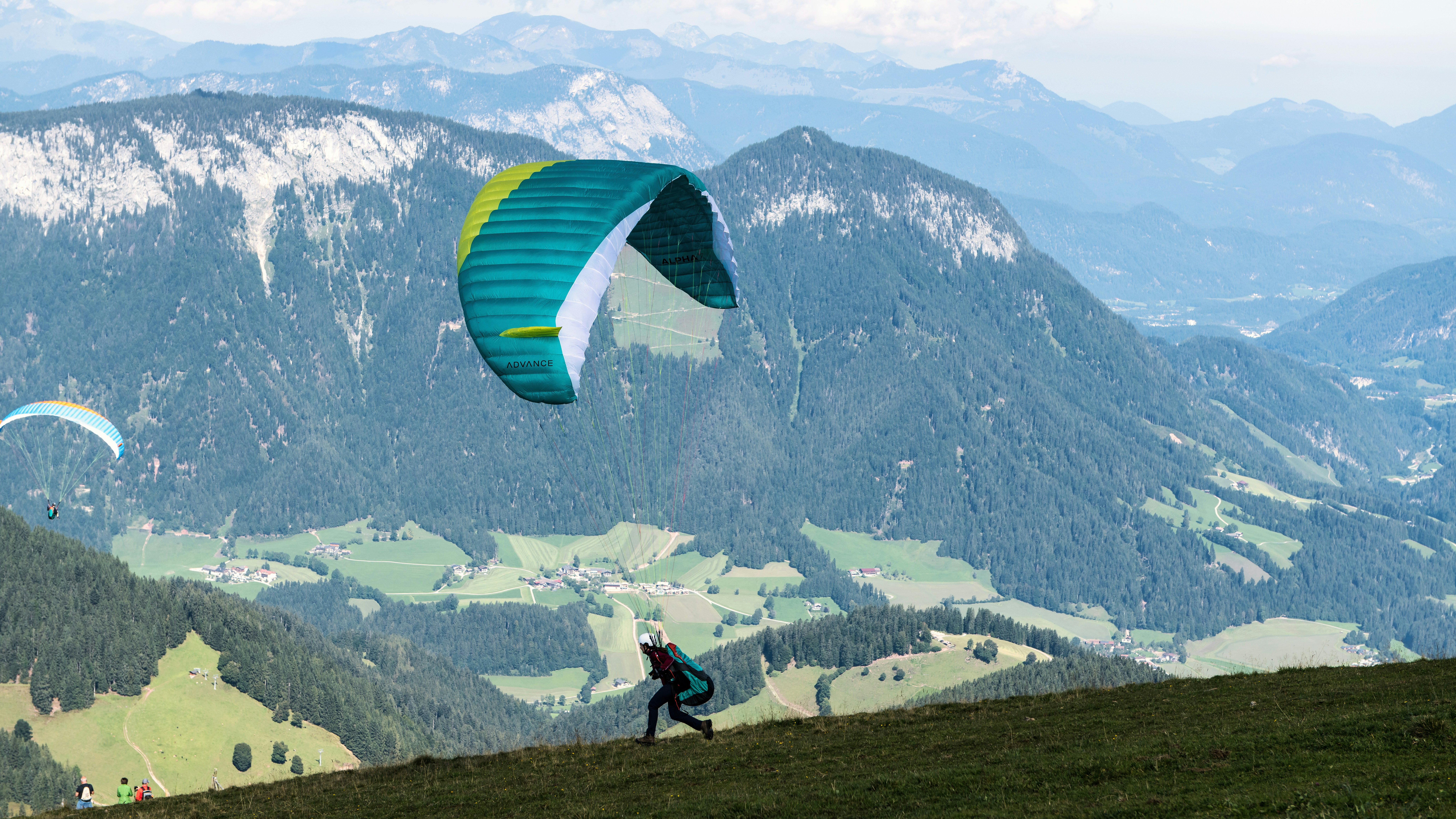 Highland Glide: A Lone Paraglider Over Alpine Valleys