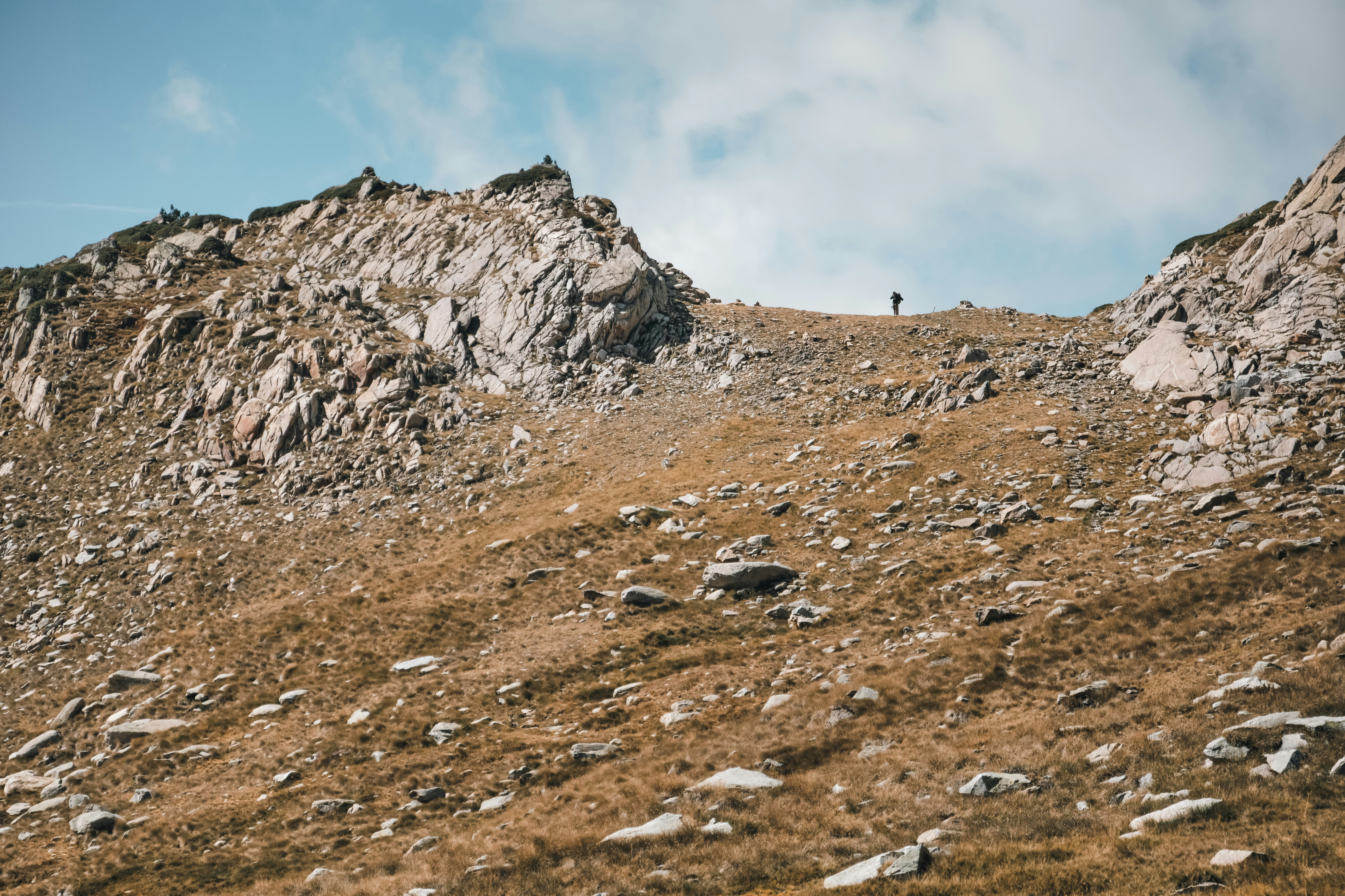 Summit Silhouette: A lone hiker on the rocky ascent