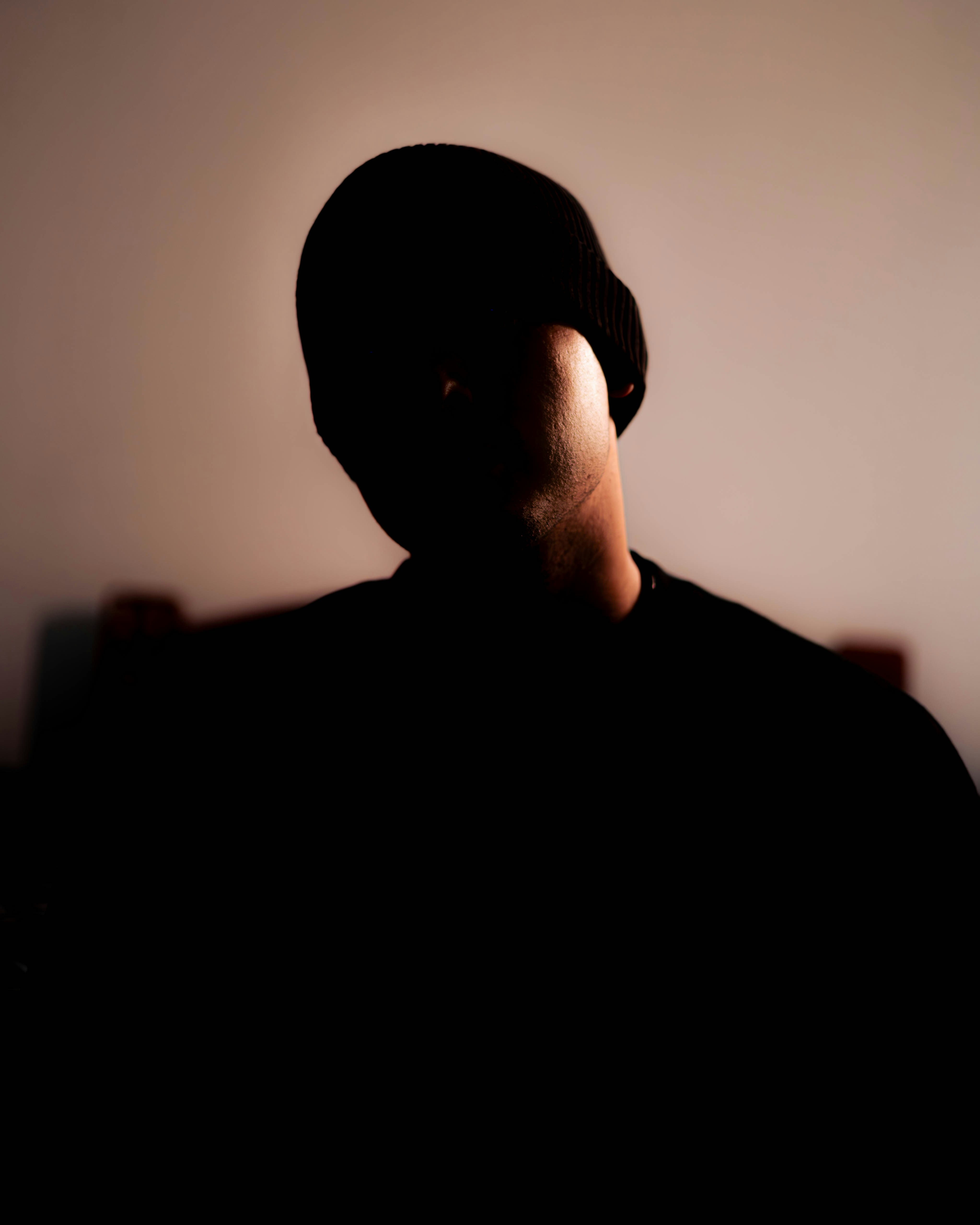 Silhouette of a person with a soft backlit edge, blurred background, and minimal facial detail. A moody, intimate portrait whose purpose emphasizes form over features. (photograph).