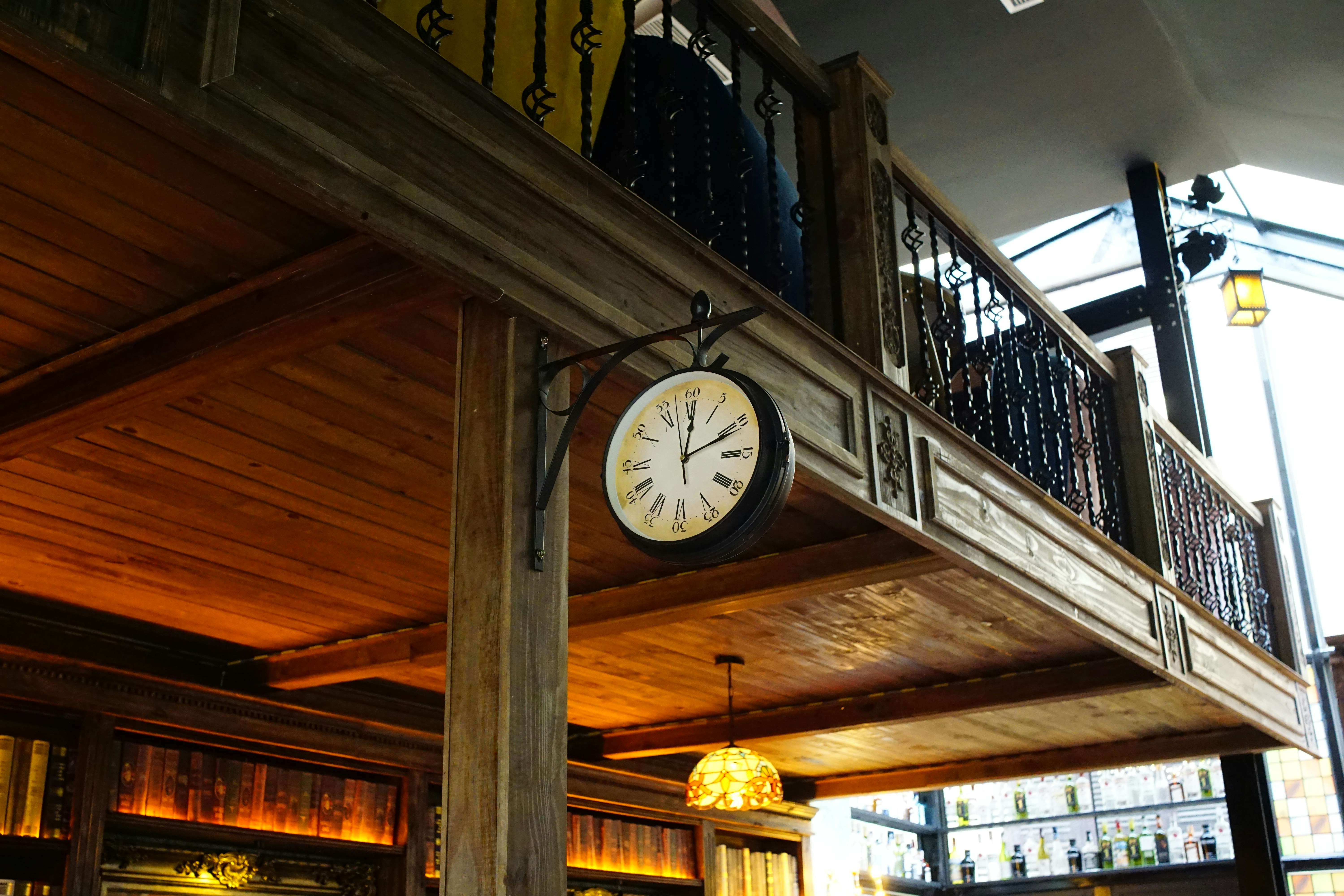 Clock over timber balcony: warm cafe lighting under a rustic loft