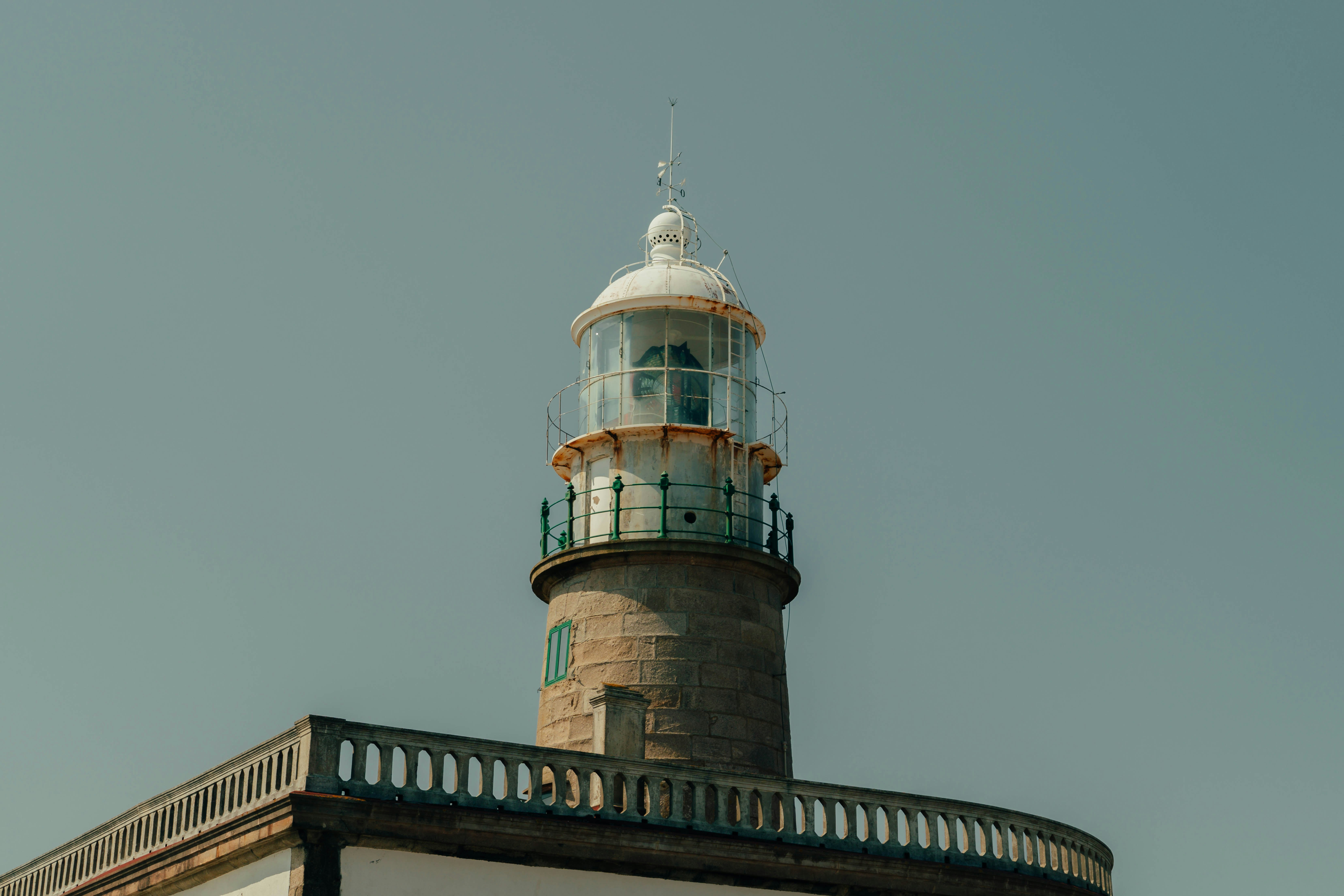 Beacon Above the Terrace: A coastal lighthouse rises over a rustic railing
