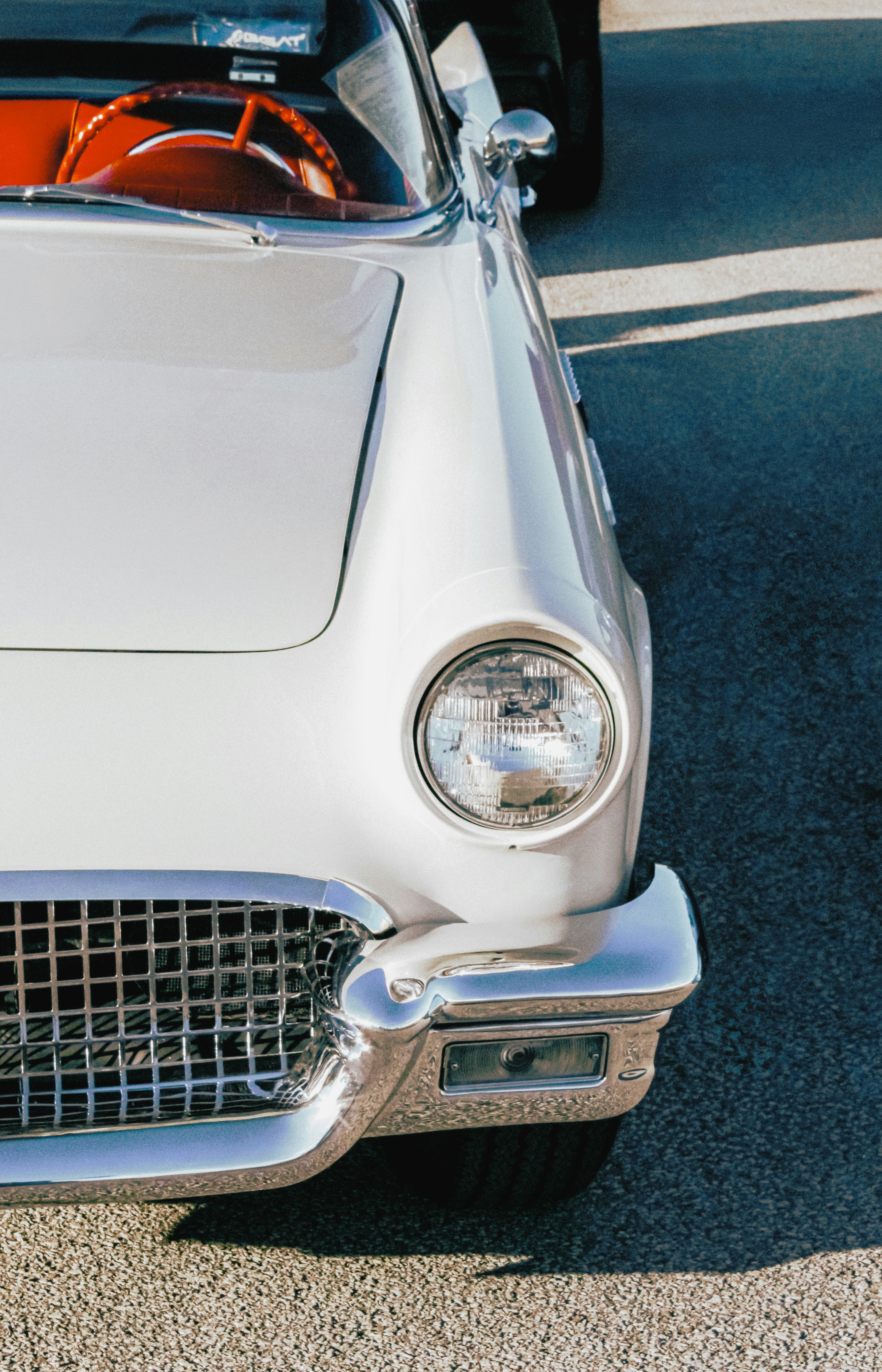 A close view of the car's front quarter, highlighting the round headlight, chrome bumper, and steep hood in bright daylight.
