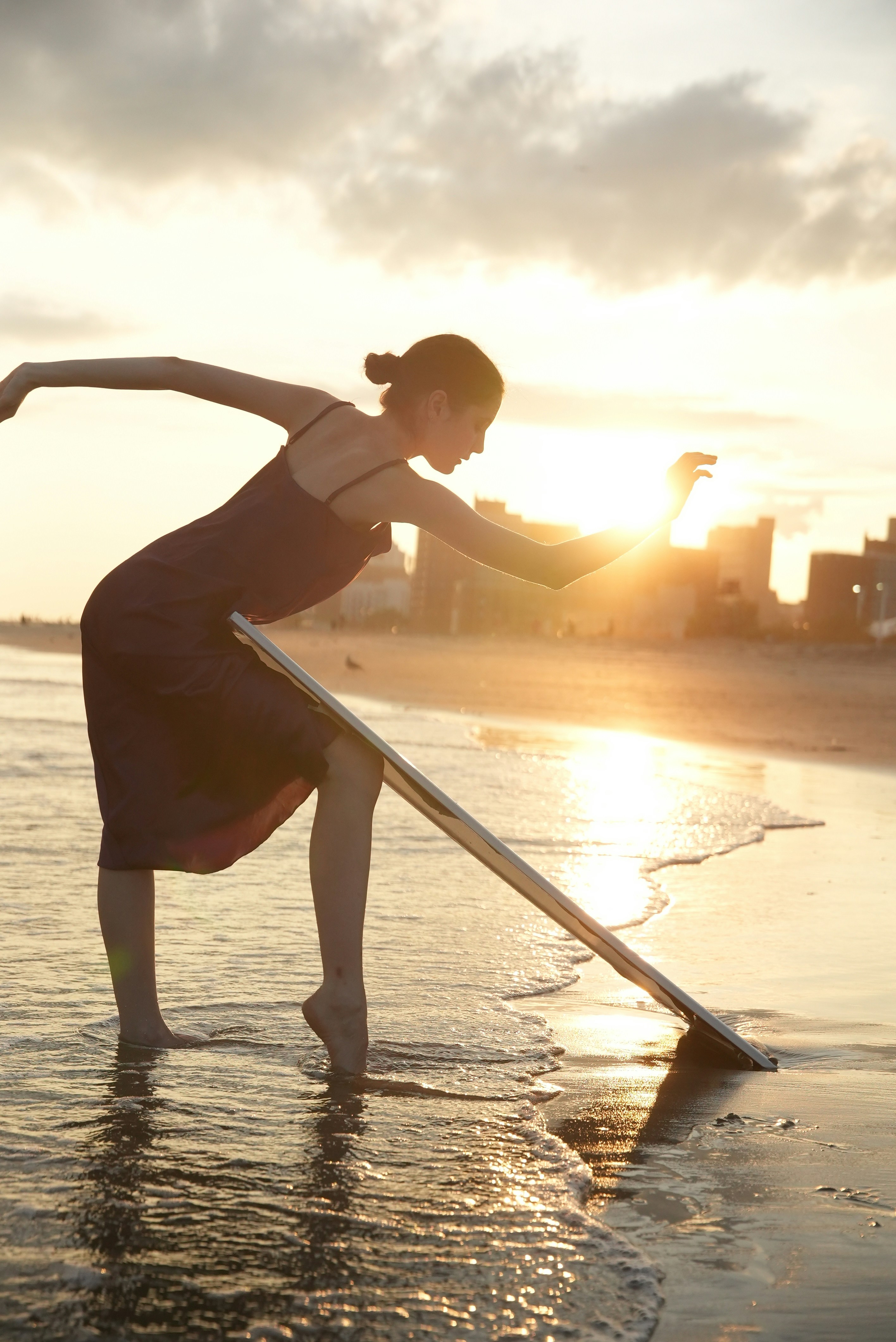 Sunlit Surf: A Dancer Shapes the Shore at Golden Hour