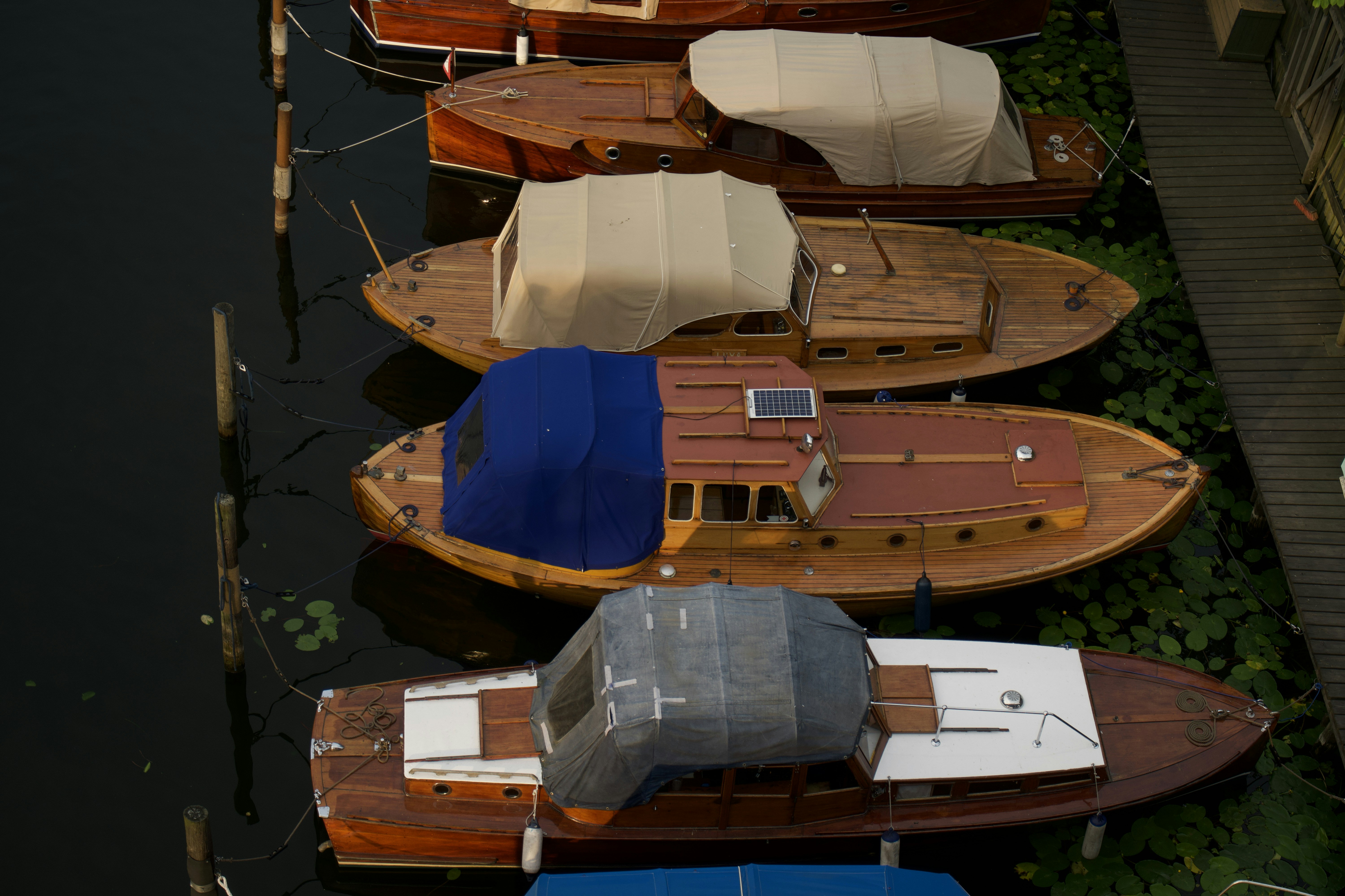 Docked wooden boats under shaded canopy on tranquil waterway