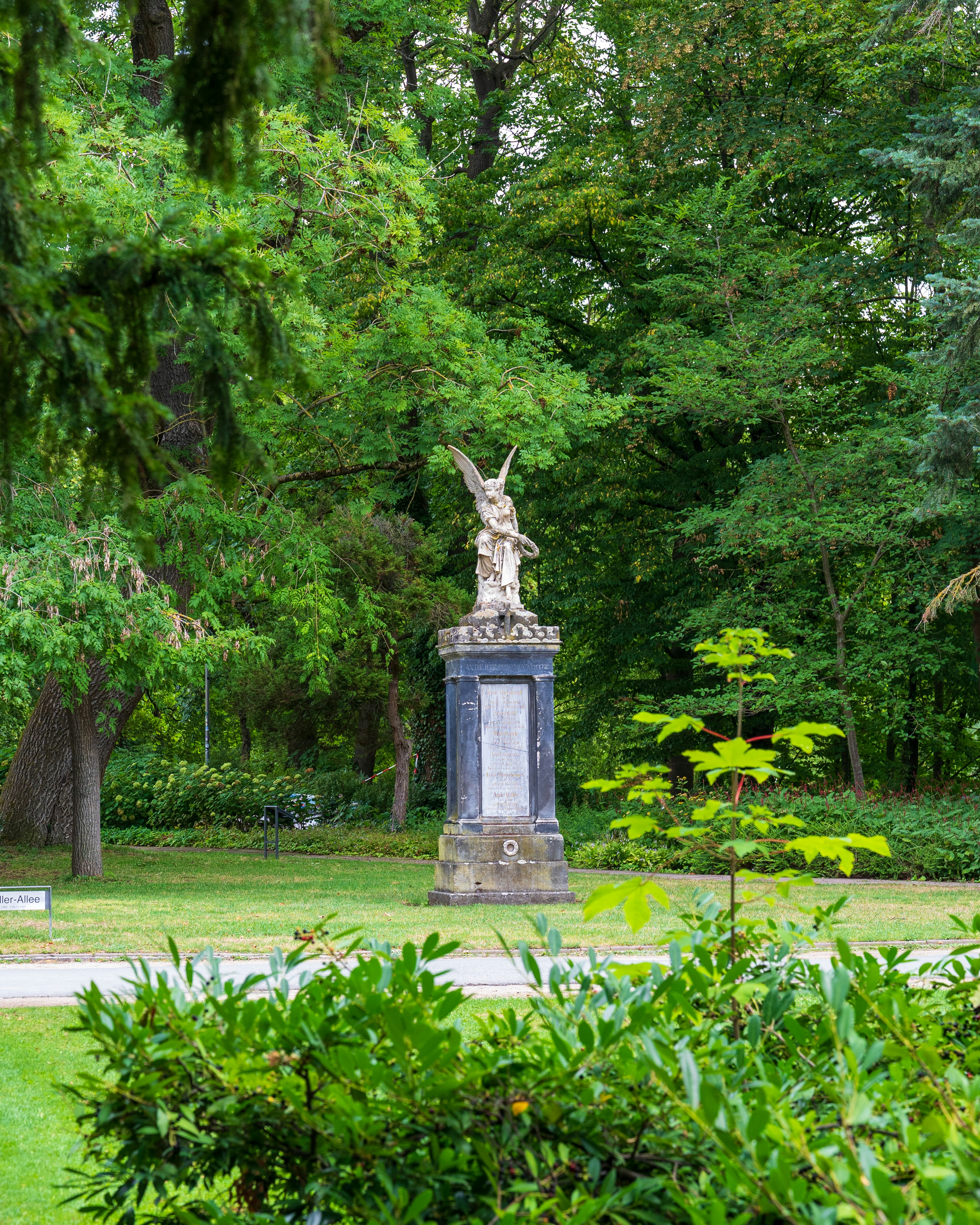 Statue Amid Green Canopy: A Garden Monument in Soft Focus