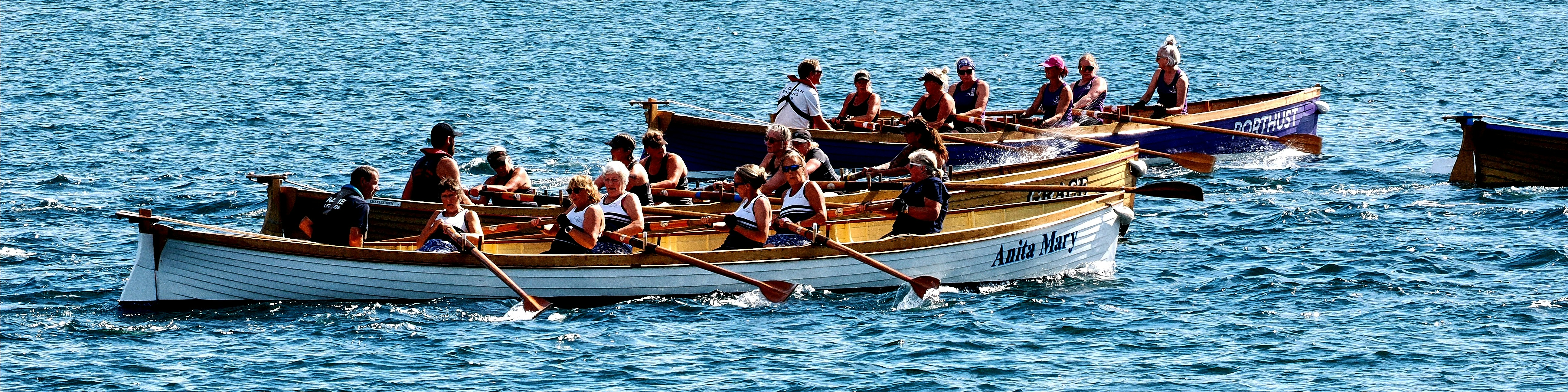 Rowers in the blue: a cluster of boats gliding on sunlit water