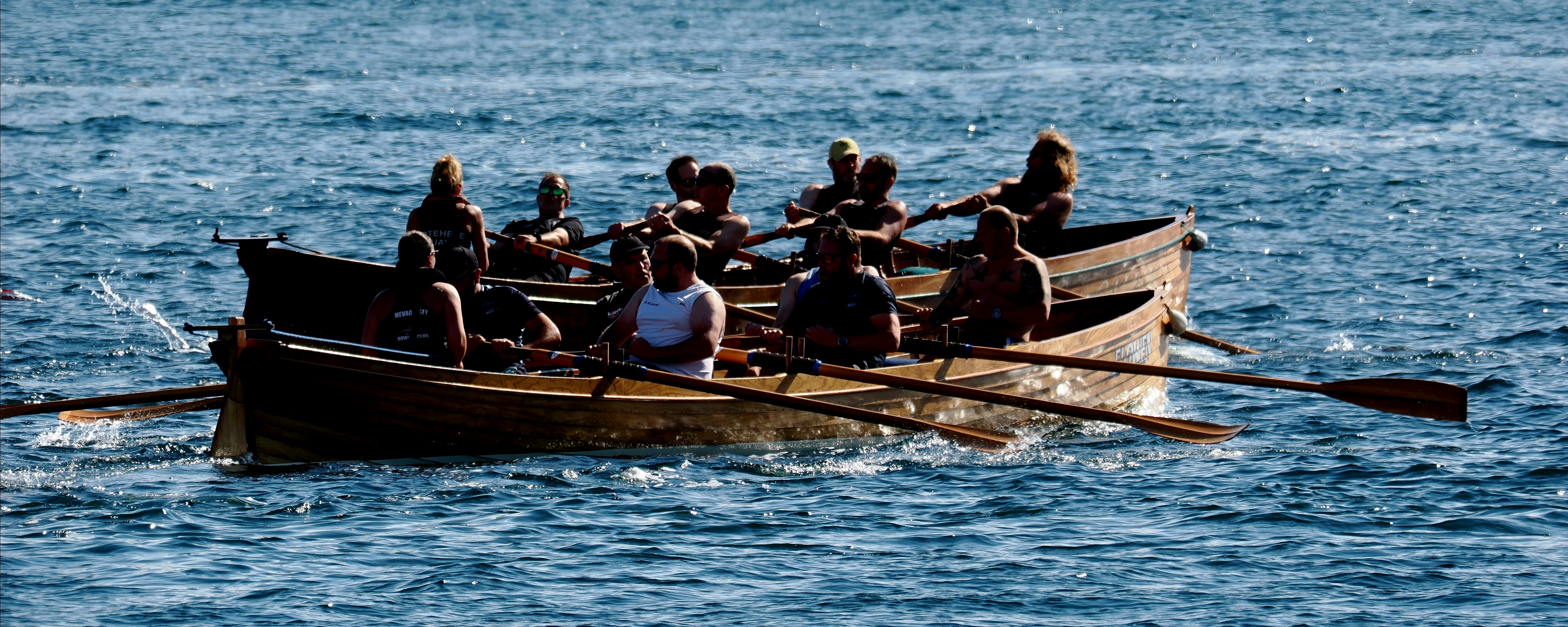 Rowers in synchronized motion across a glimmering sea