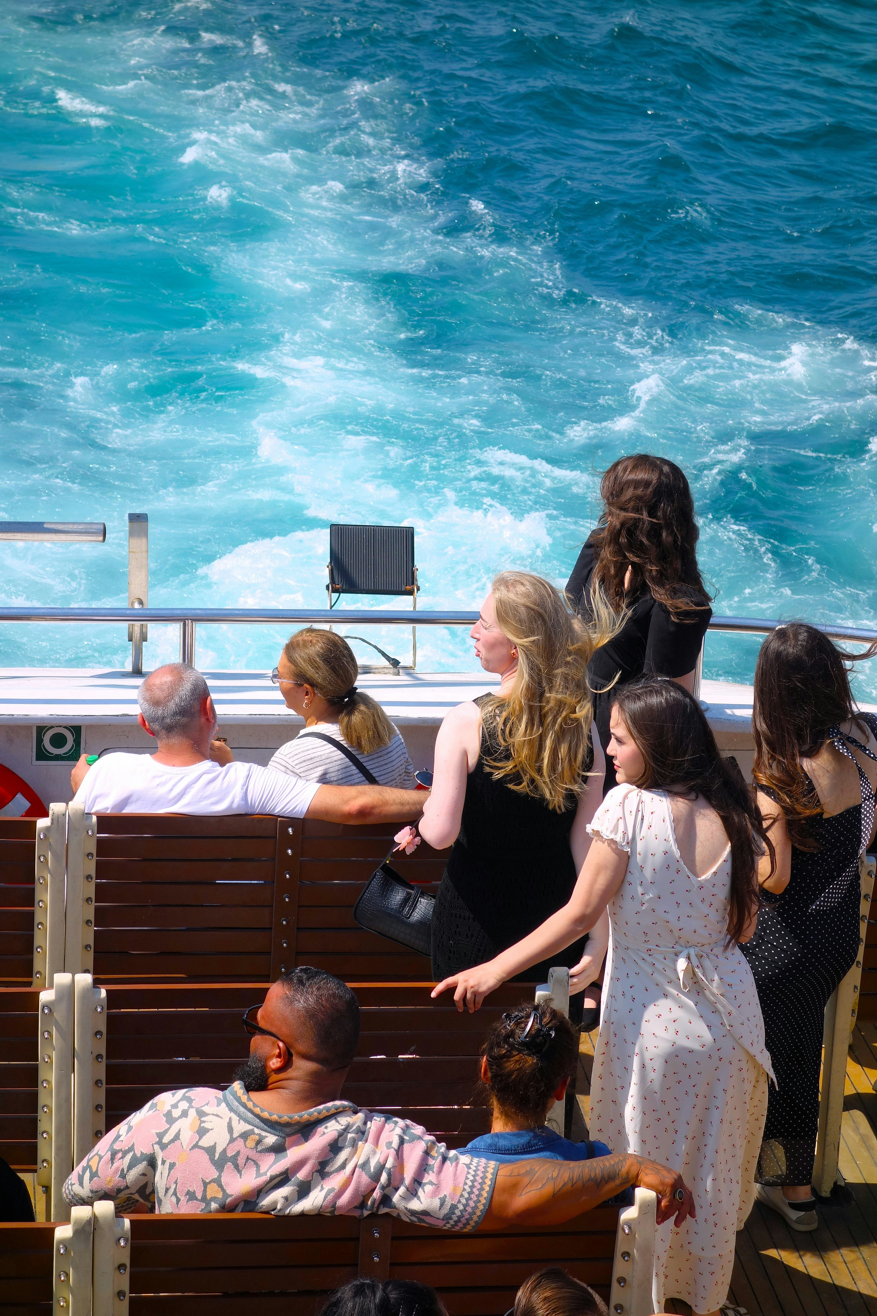 Sunlit Horizon: Passengers Overlook the Sea from a Cruise Deck