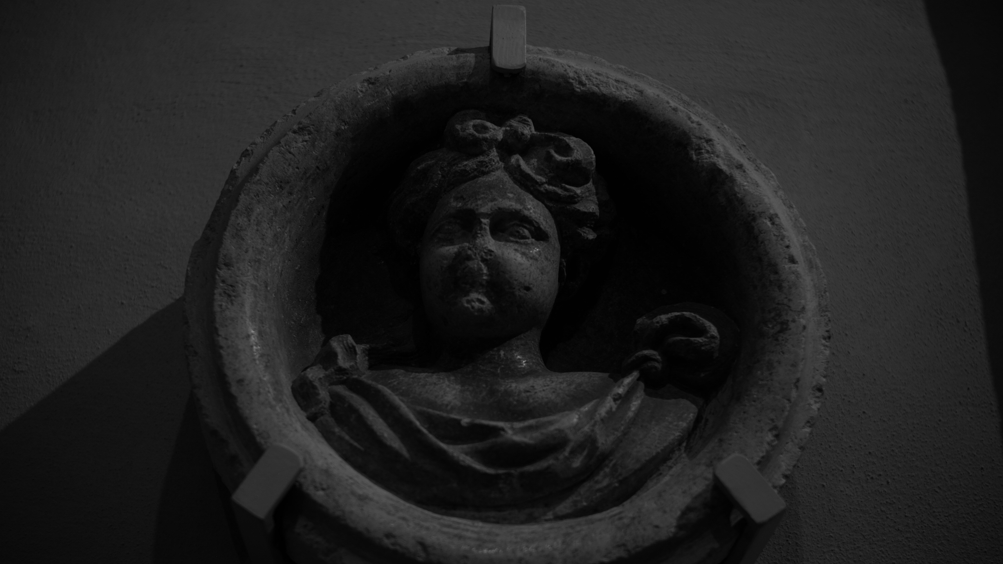 Stone Guardian: A Weathered Carved Face Peering from the Arch