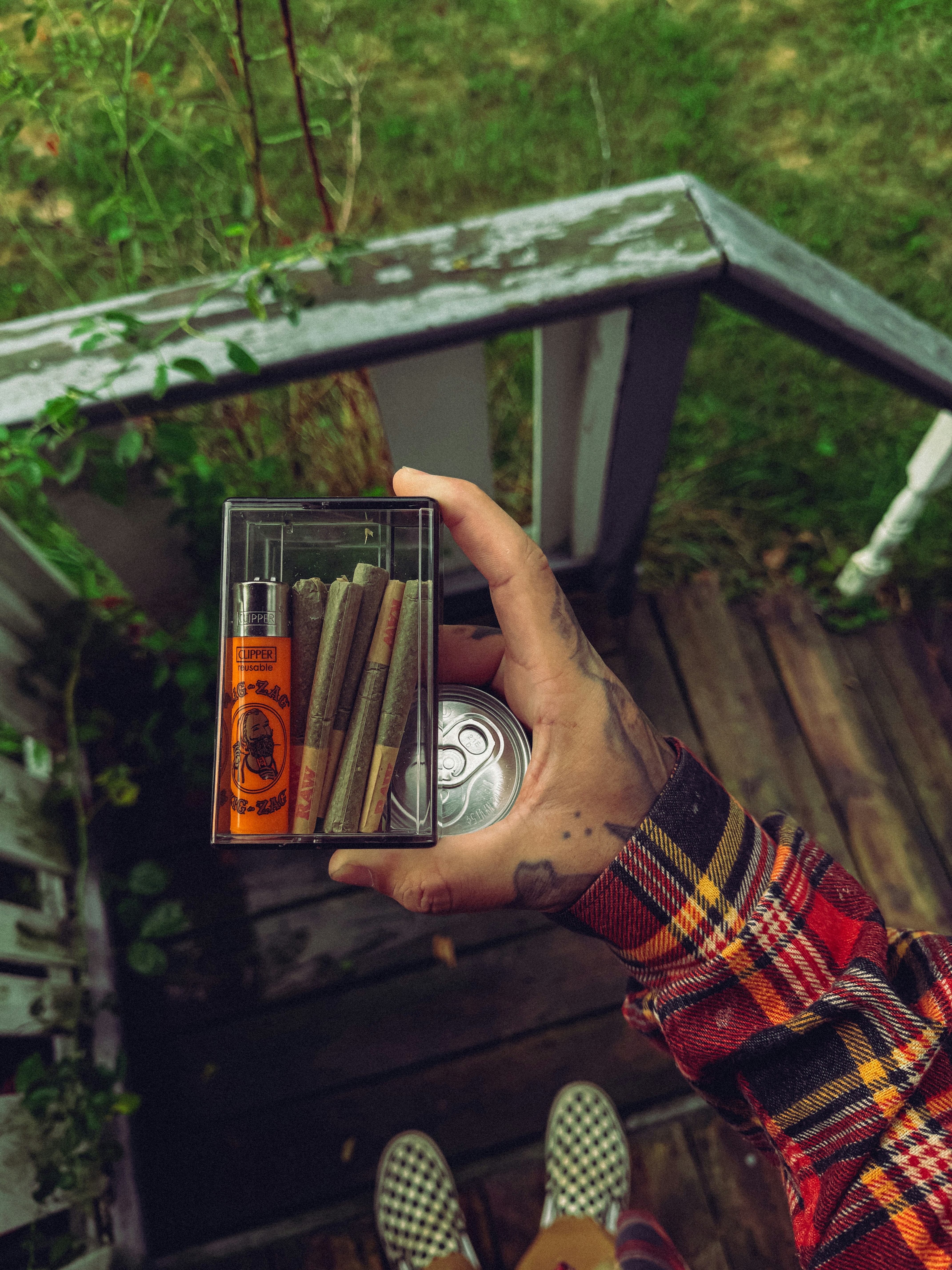 Handheld snapshot of a compact moody cigarette case and beverage can from a first-person descending vantage