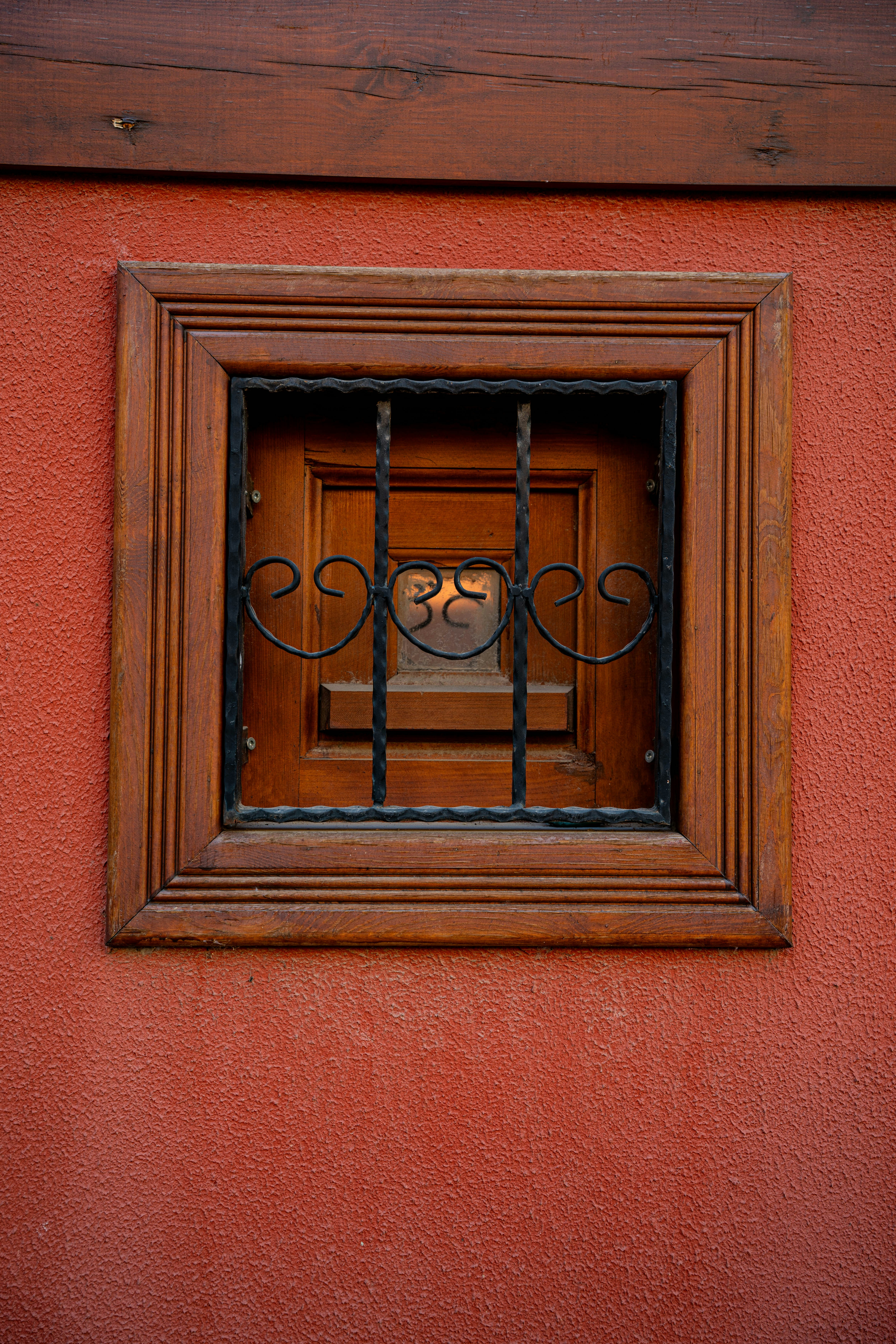 Iron Grilles and Warm Wood: A Window Portrait in Red Plaster