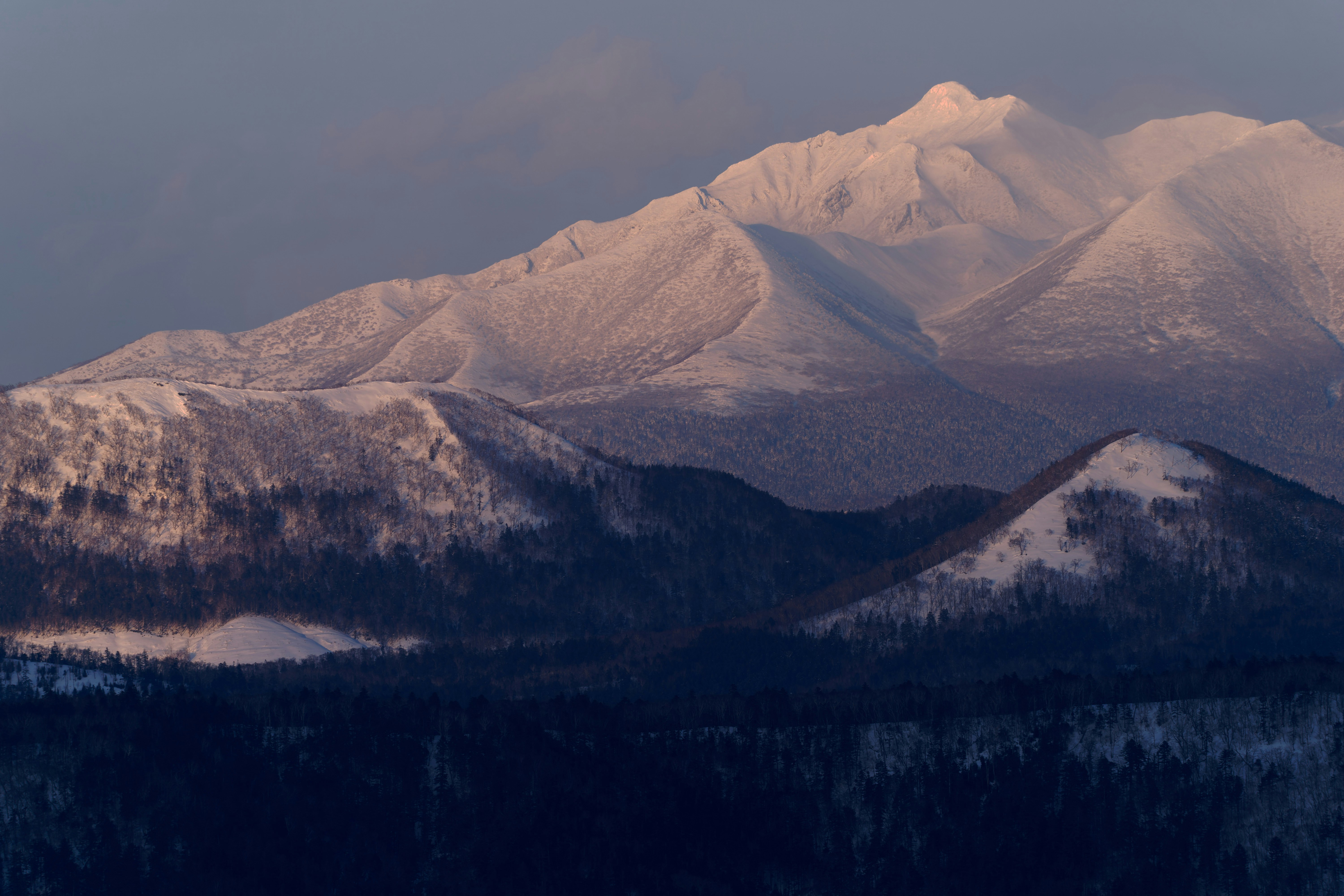 Snow-Capped Peaks at Dusk: A Quiet Ridge Under Pink-tinged Sky