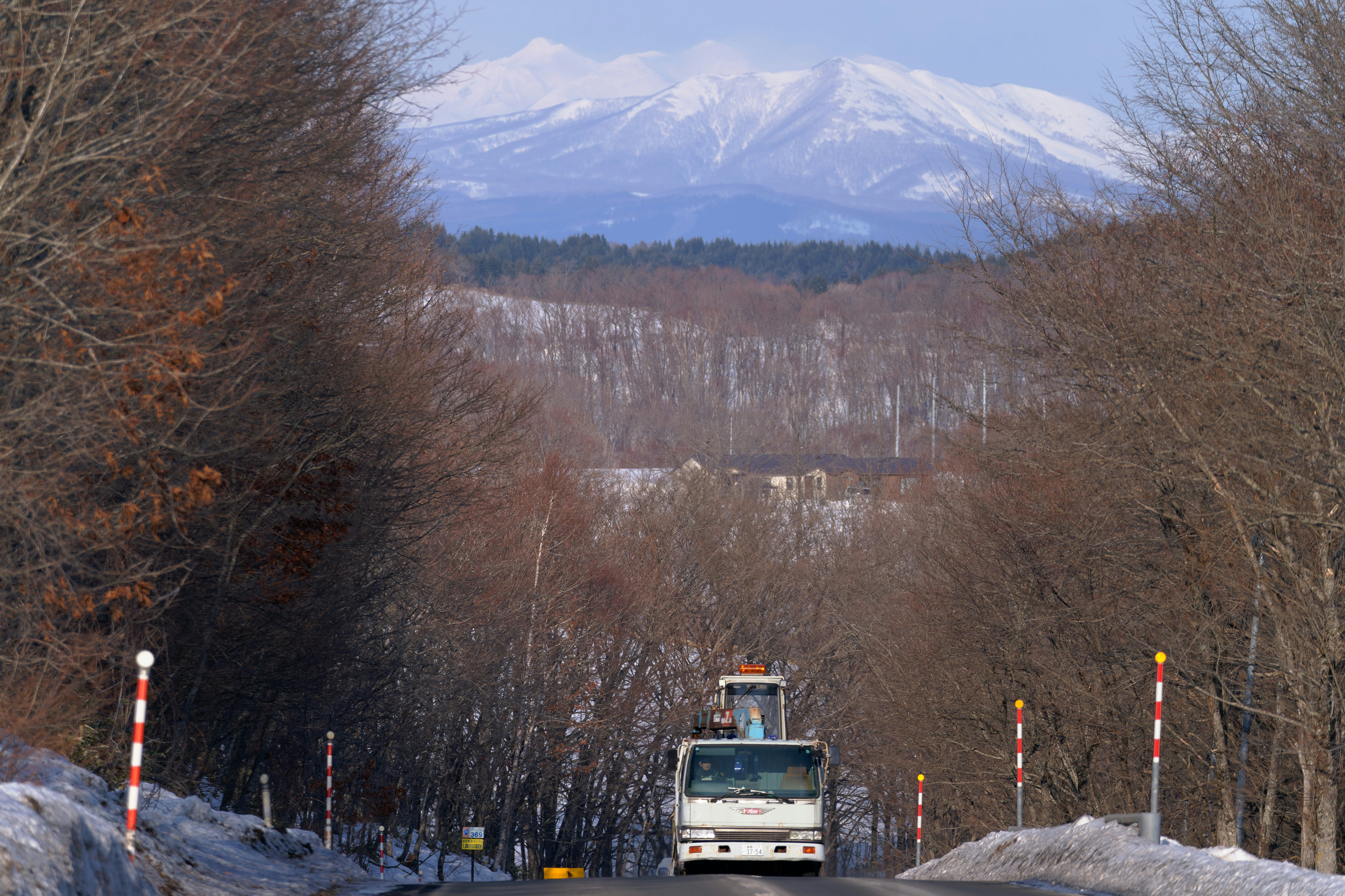 Snowy Mountain Road Trucker Under a Watery Blue Sky